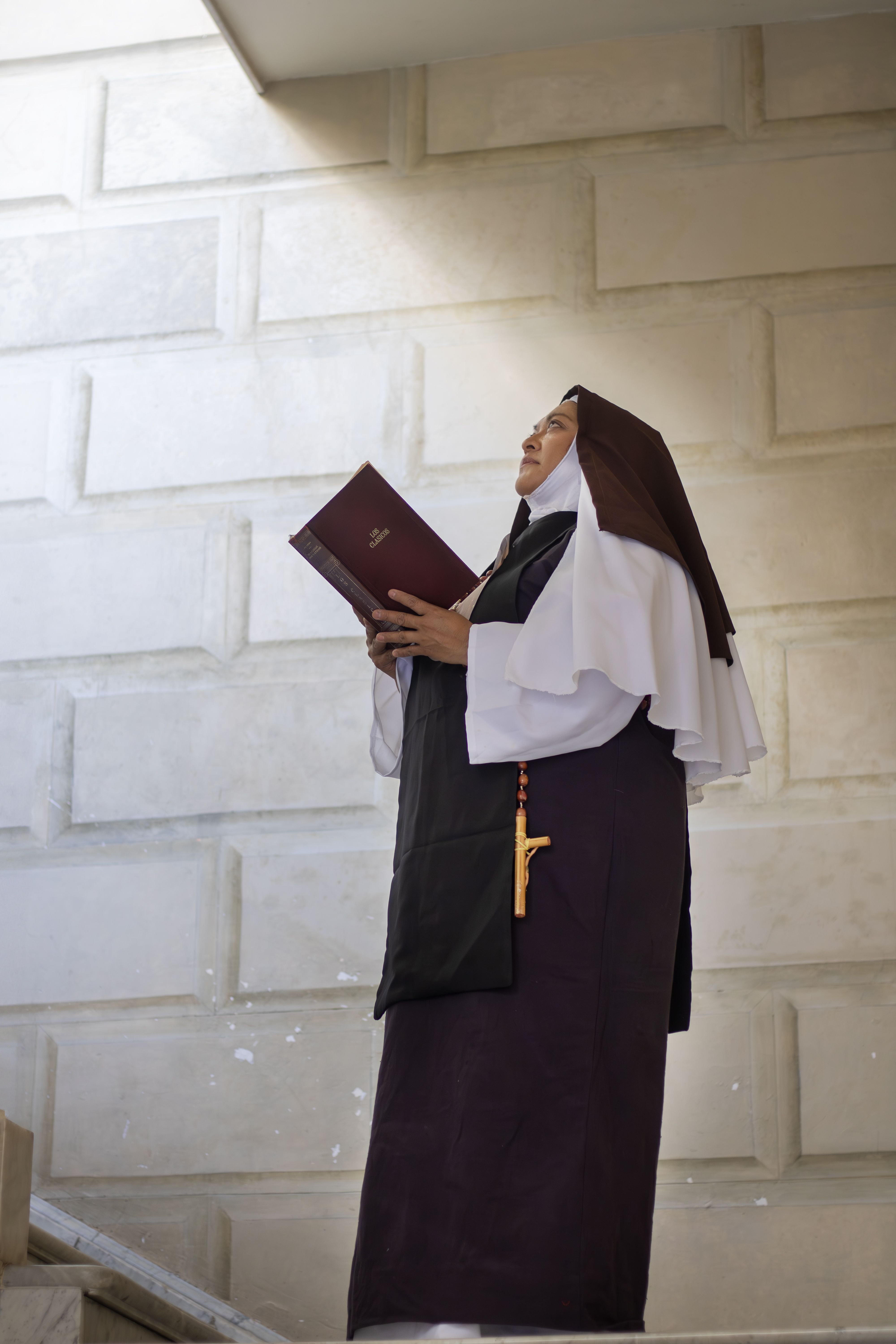 A nun is standing on a set of stairs holding a book · Free Stock Photo