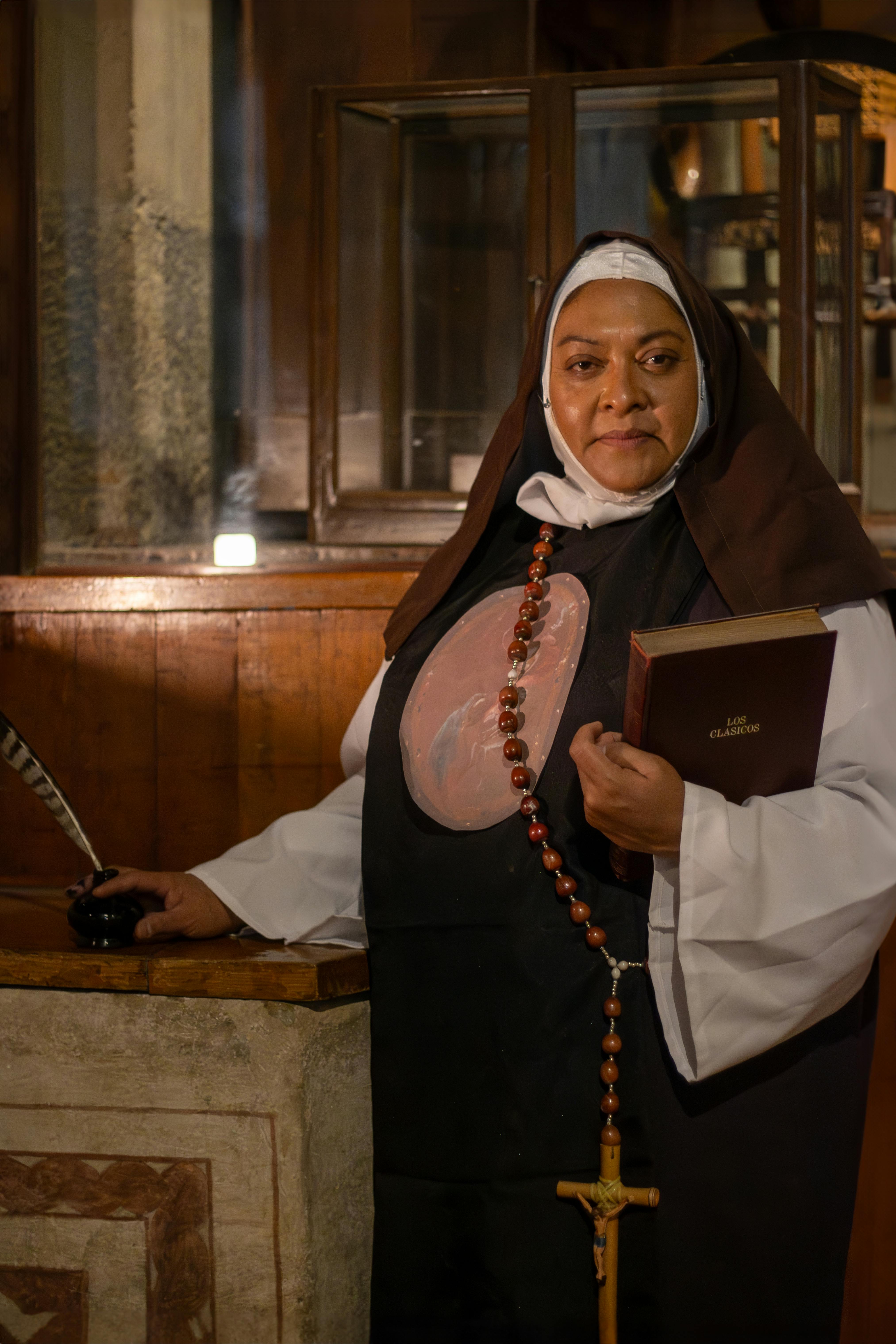 A nun holding a book and writing on a table · Free Stock Photo