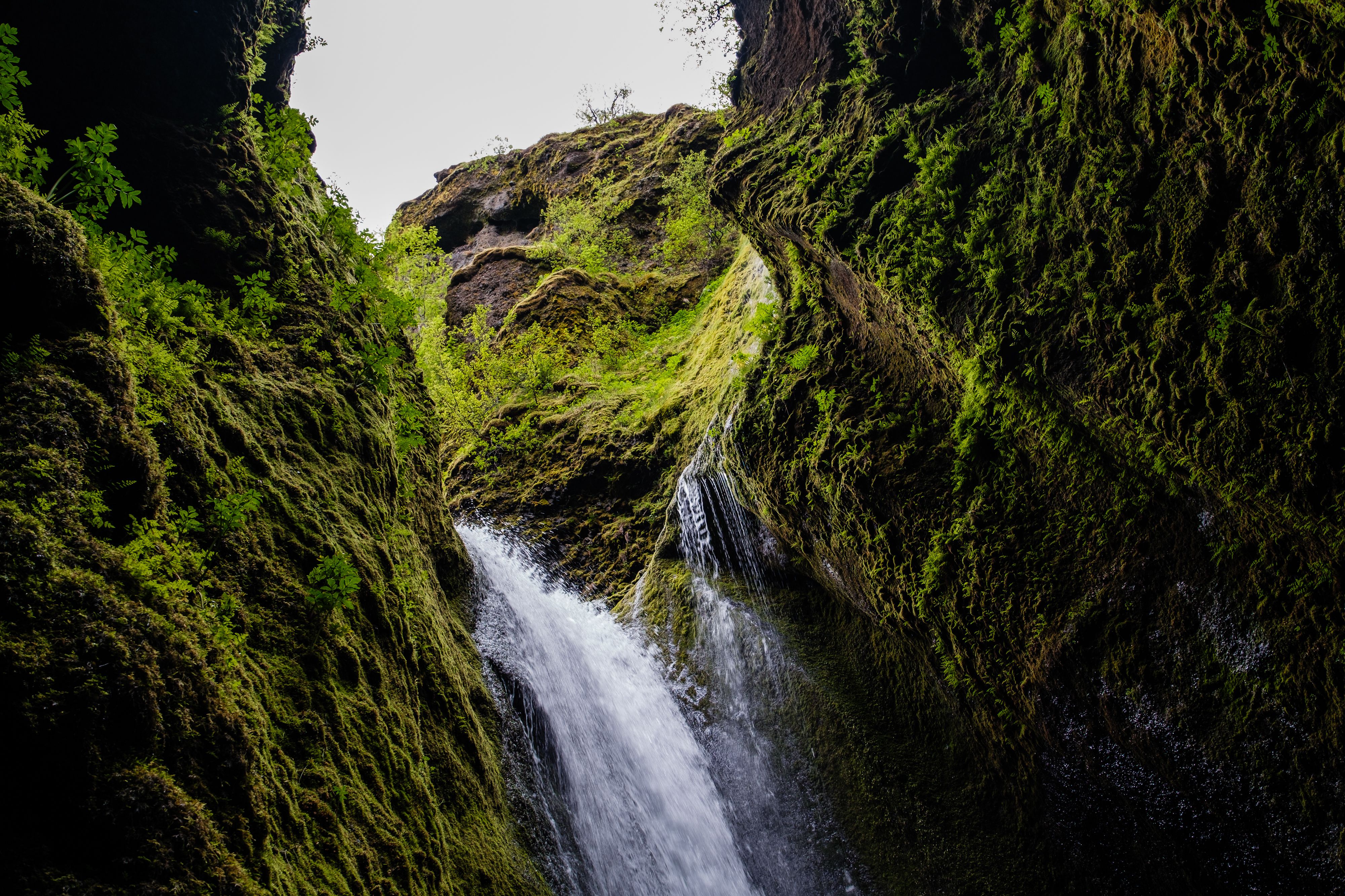 A waterfall is flowing through a narrow canyon · Free Stock Photo