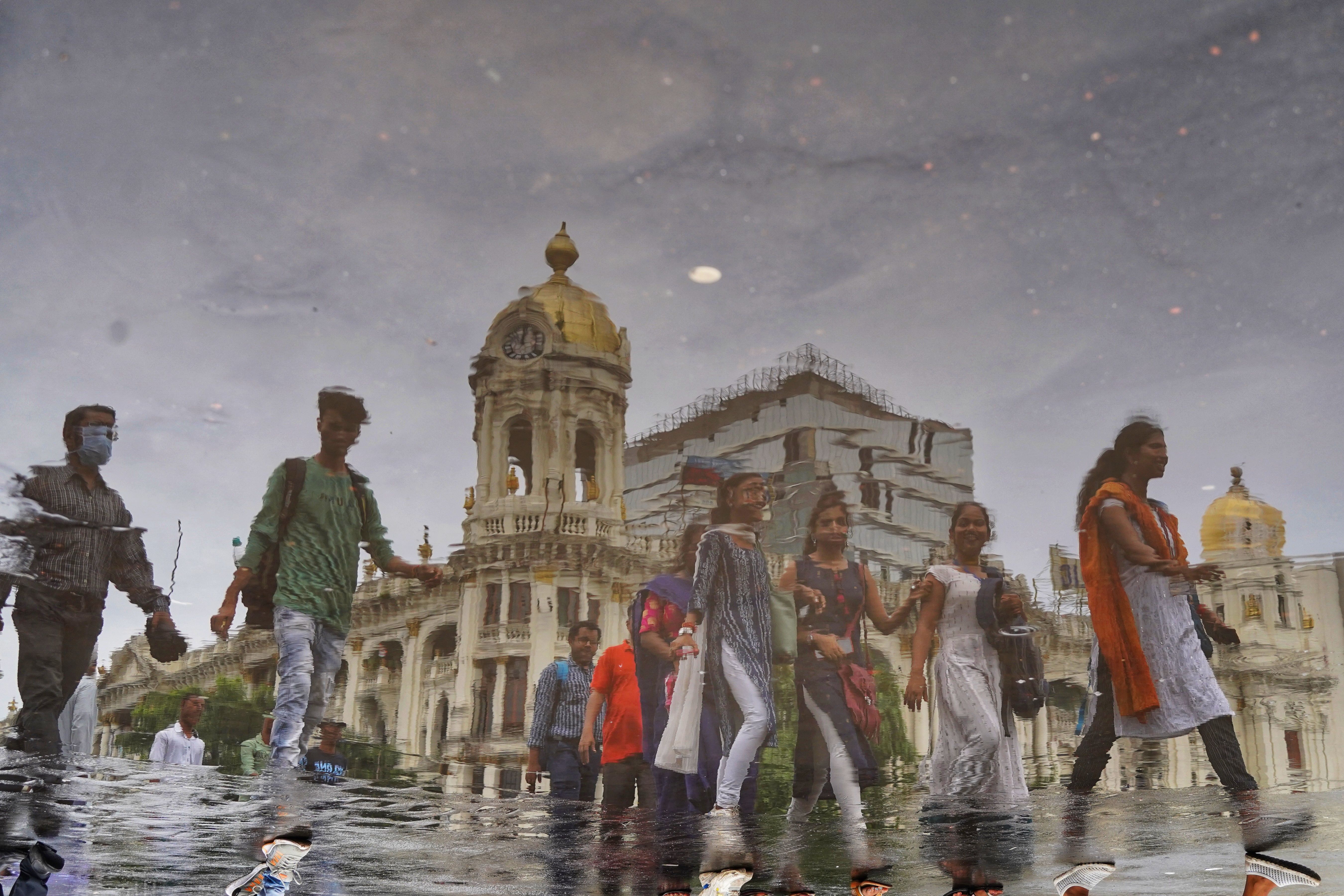 Reflection in a Puddle of People Walking against Indian Architecture ...