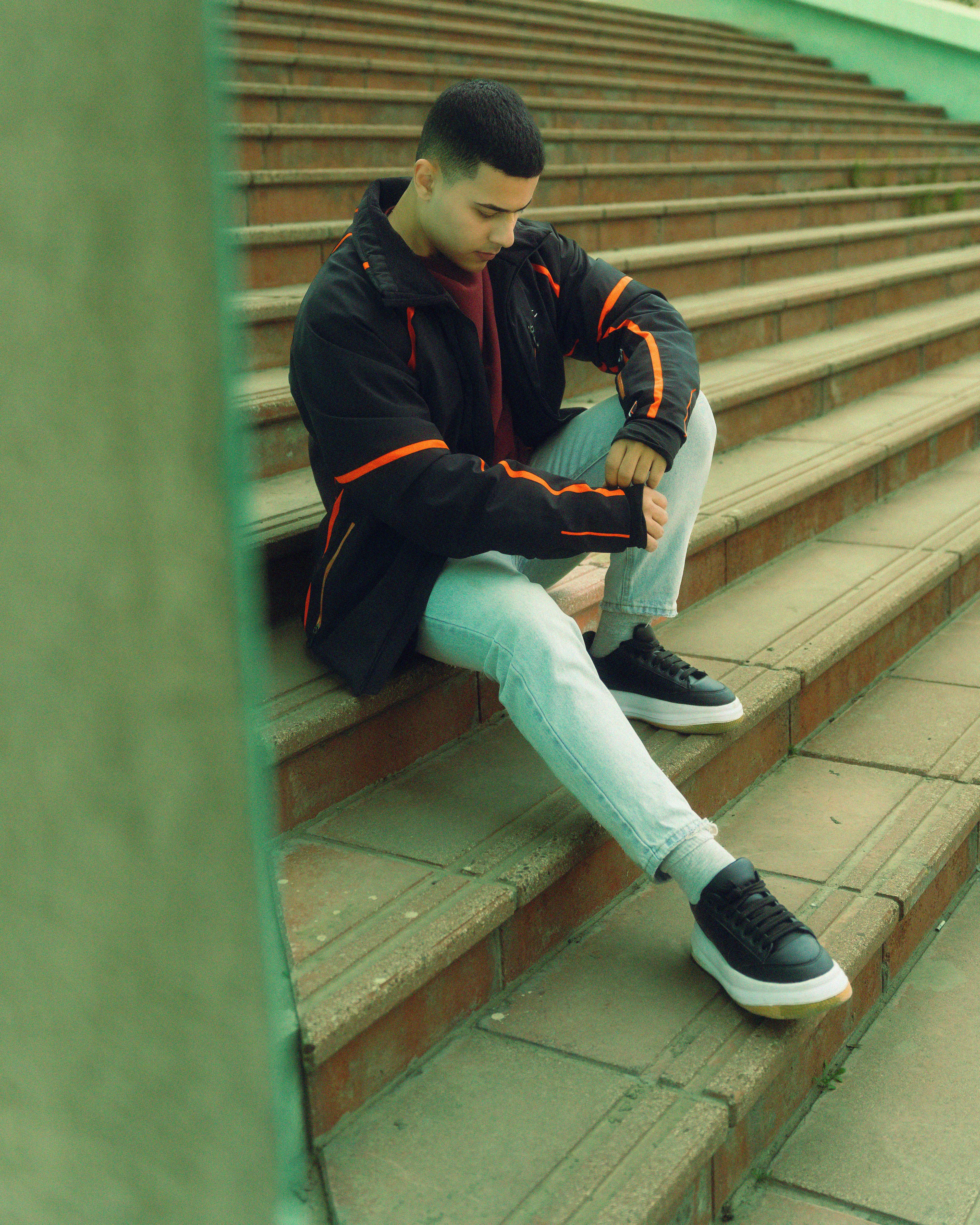 A man sitting on some steps with his shoes off · Free Stock Photo