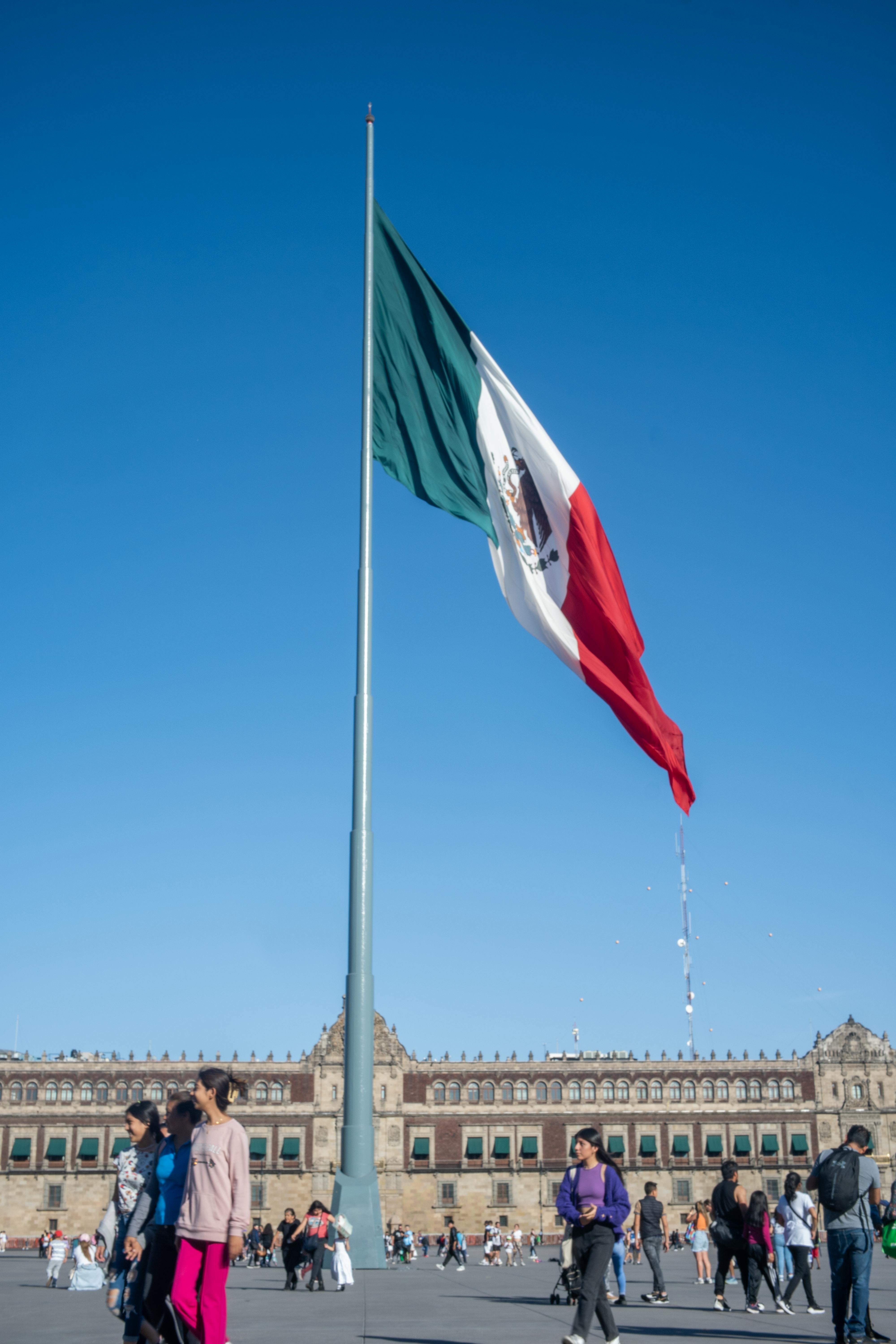 A mexican flag flying in front of a building · Free Stock Photo