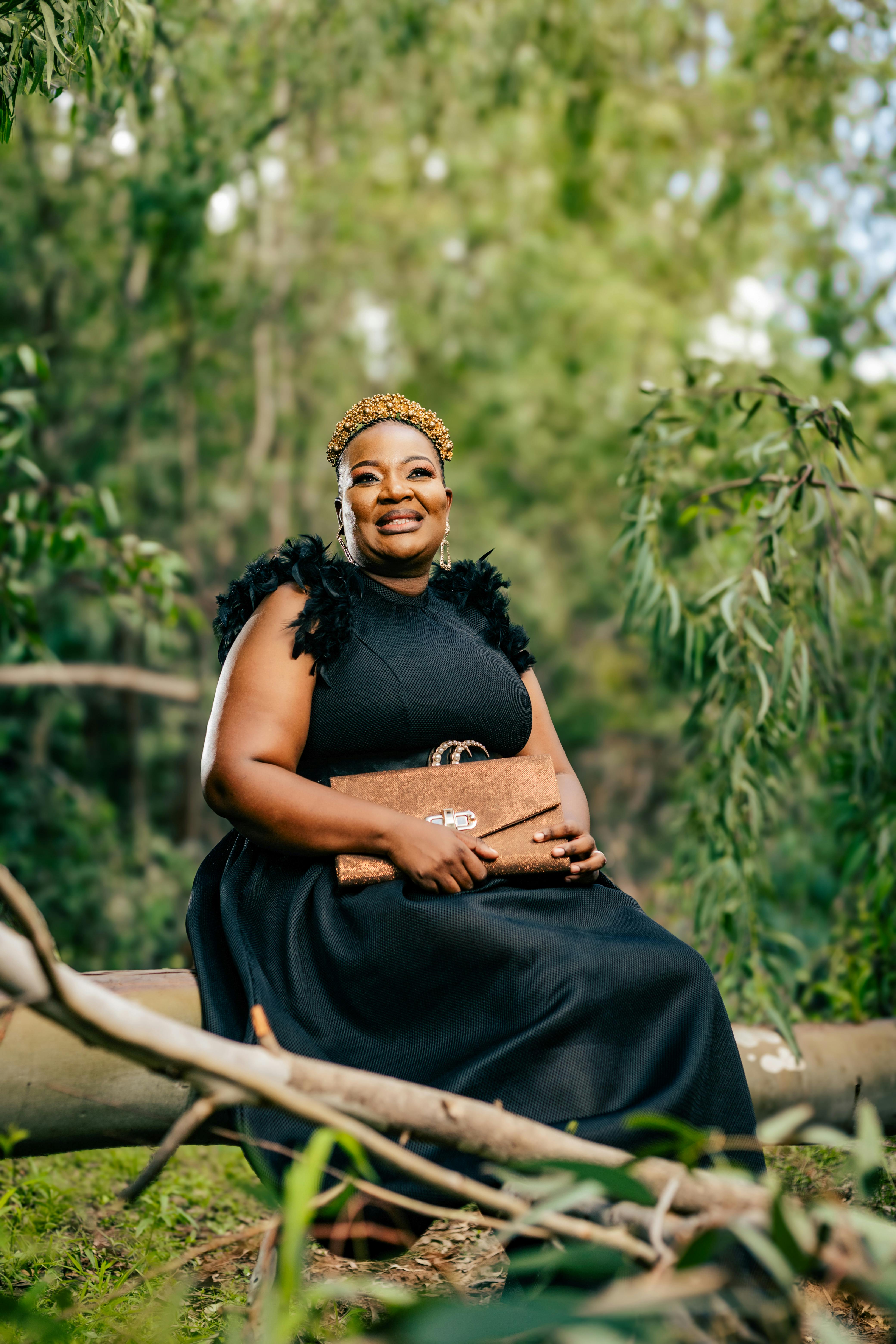 A woman in a black dress sitting on a tree · Free Stock Photo