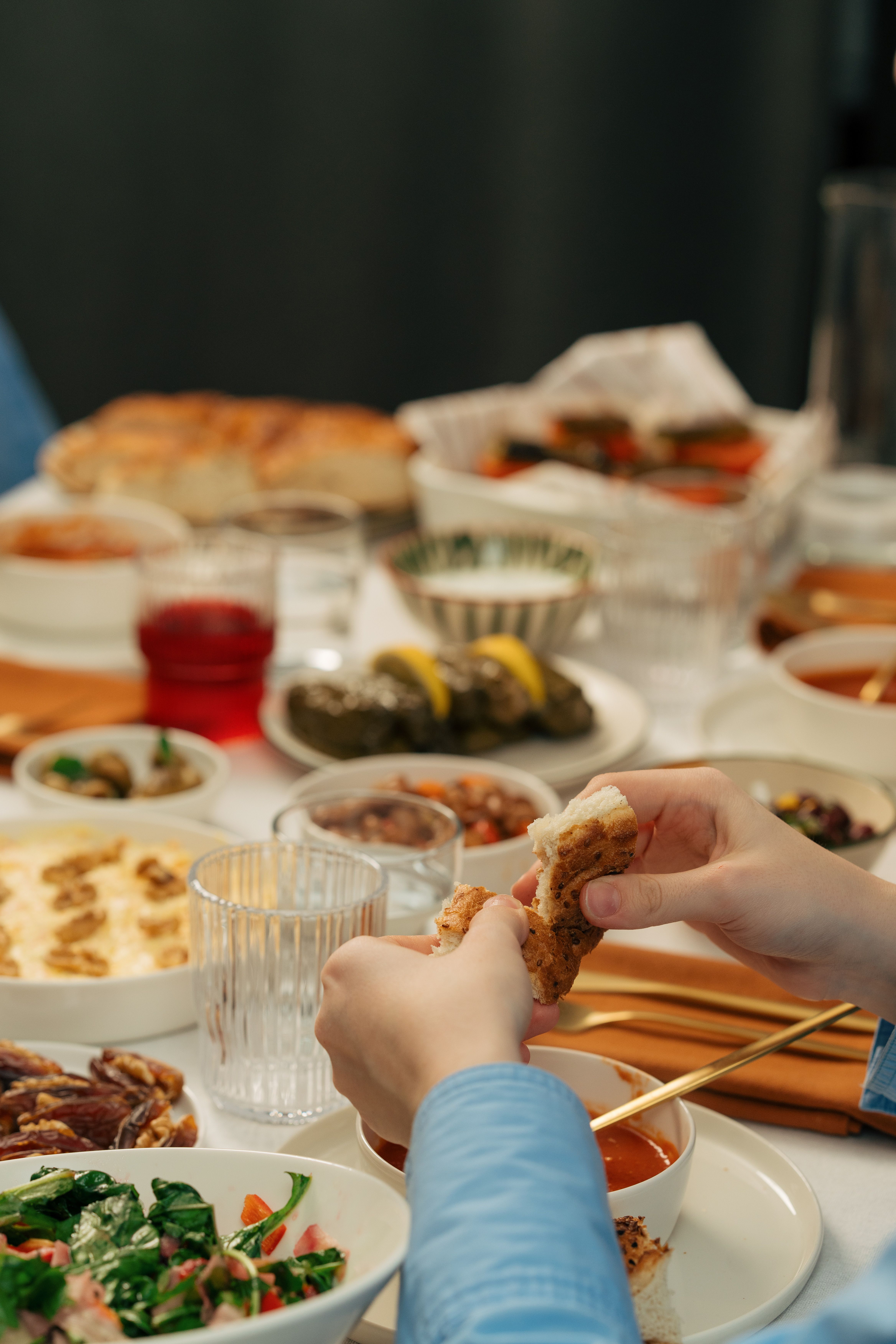 A person eating food at a table with plates and bowls · Free Stock Photo