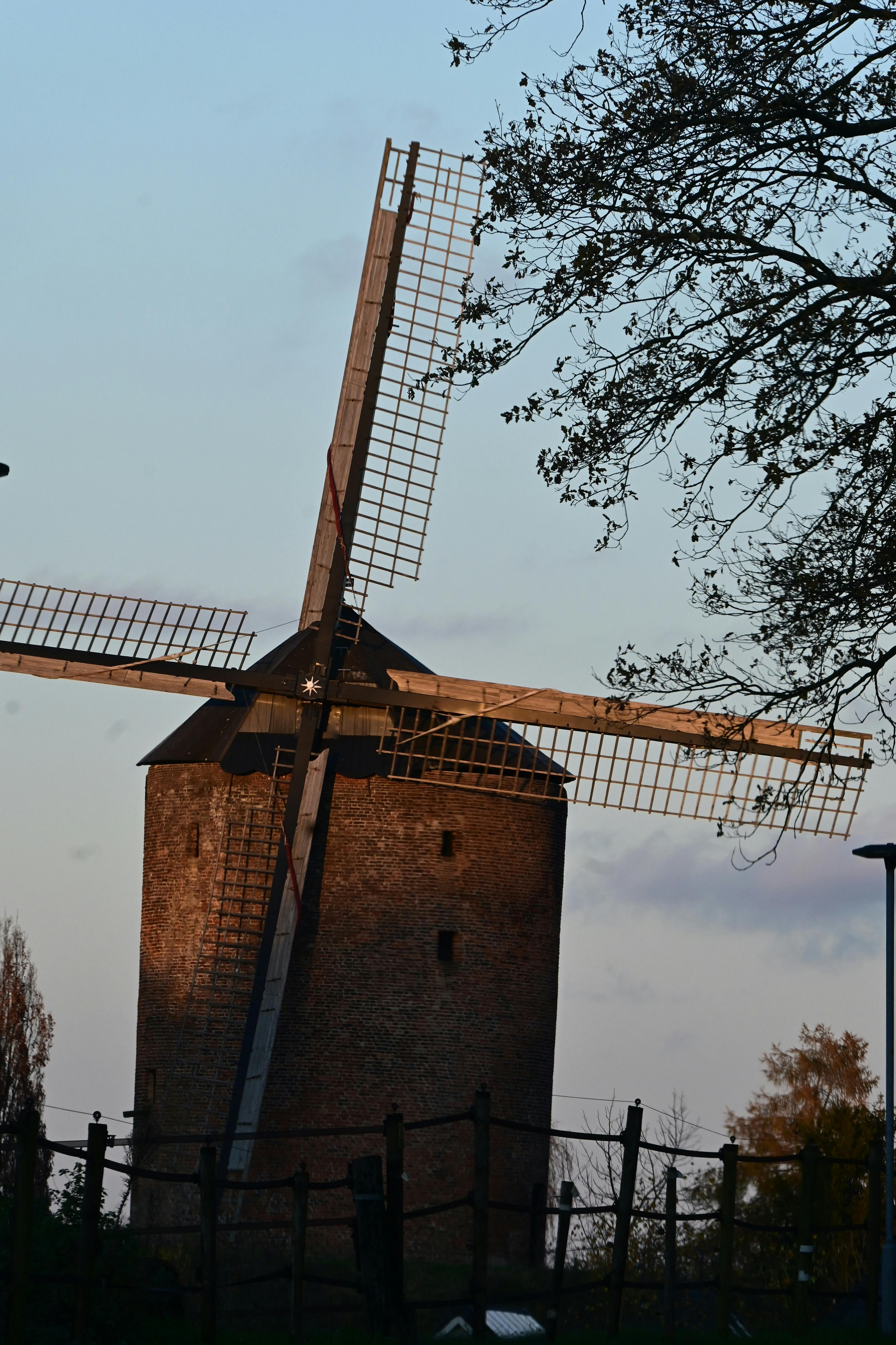 A windmill is in the foreground of a picture · Free Stock Photo