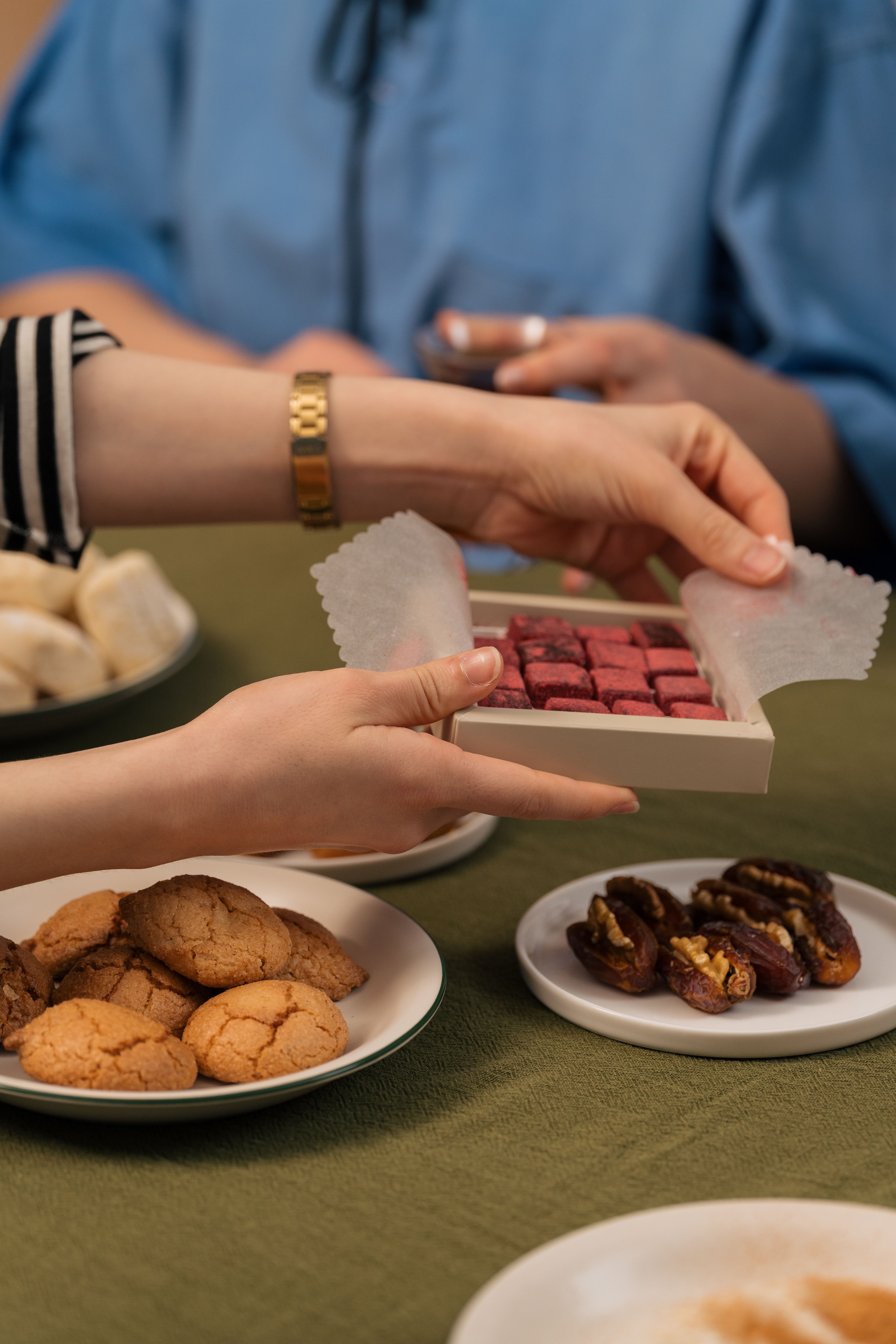 Woman Hands Holding Box of Sweets over Plates on Table · Free Stock Photo