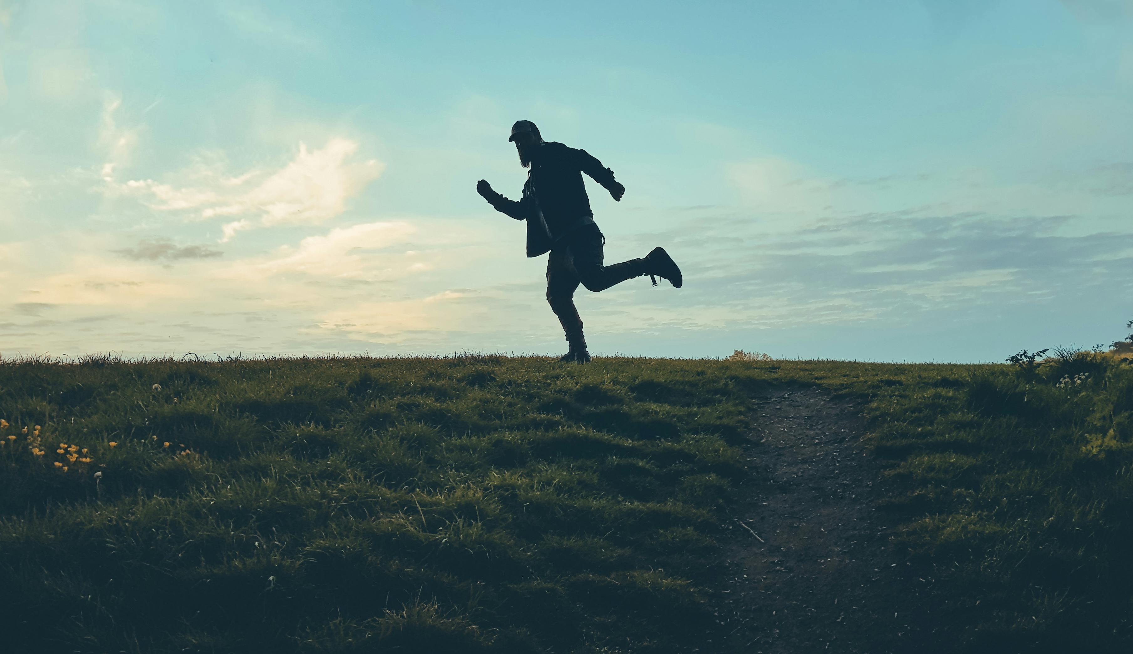 A person running on a hill at sunset · Free Stock Photo