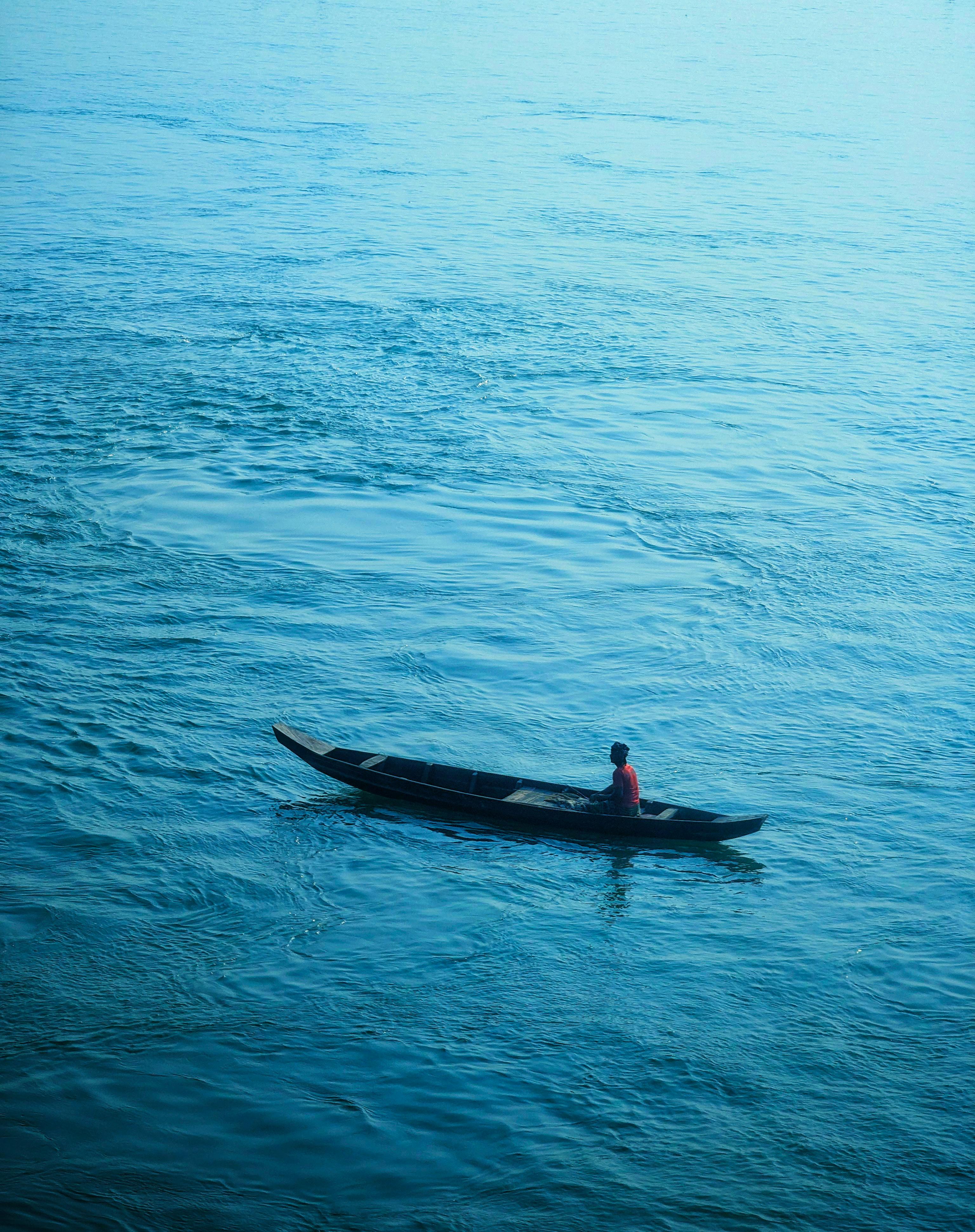 Person Sitting Alone on Boat on Blue Water · Free Stock Photo