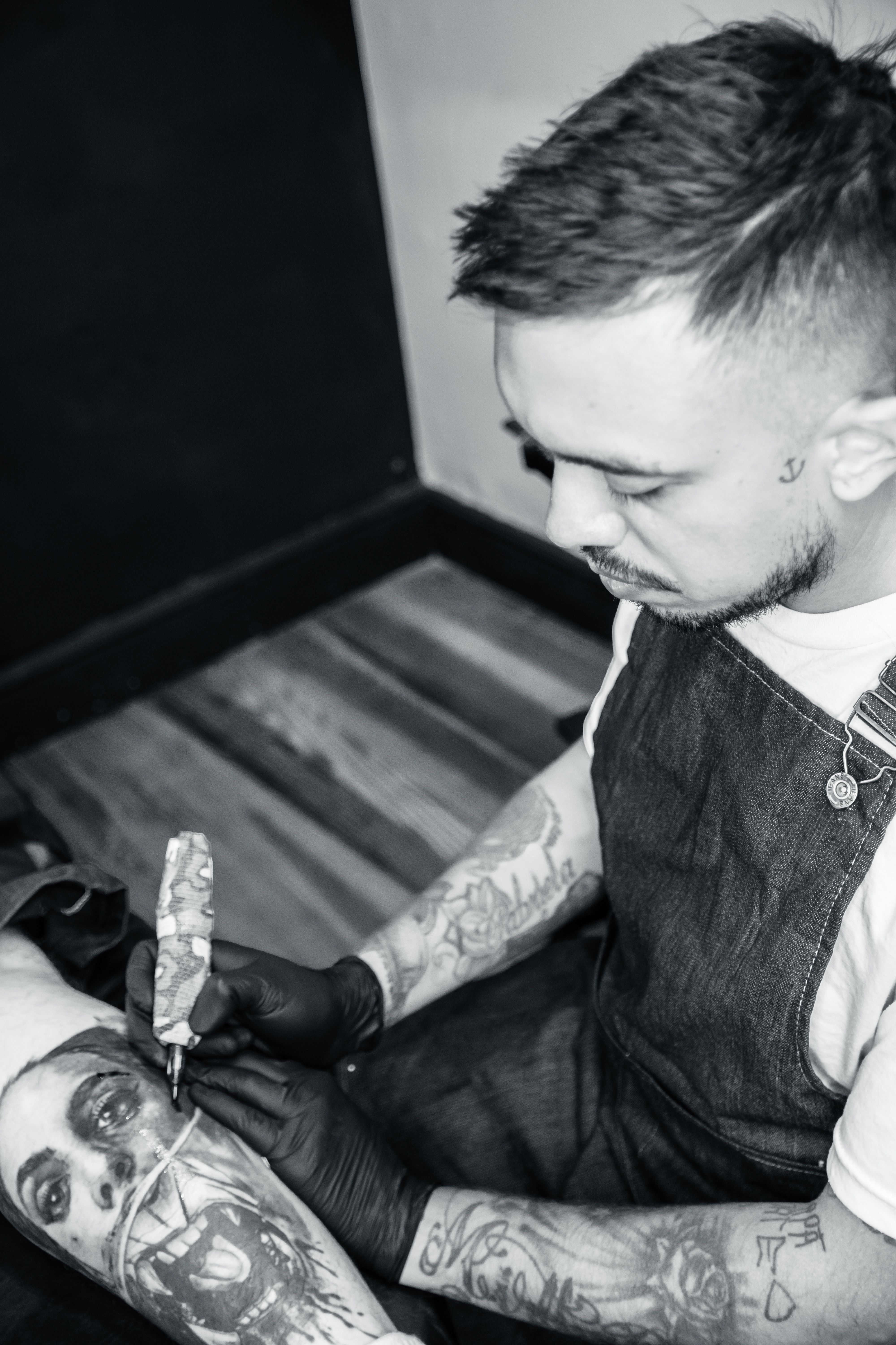 Black and White Photograph of a Man Tattooing · Free Stock Photo