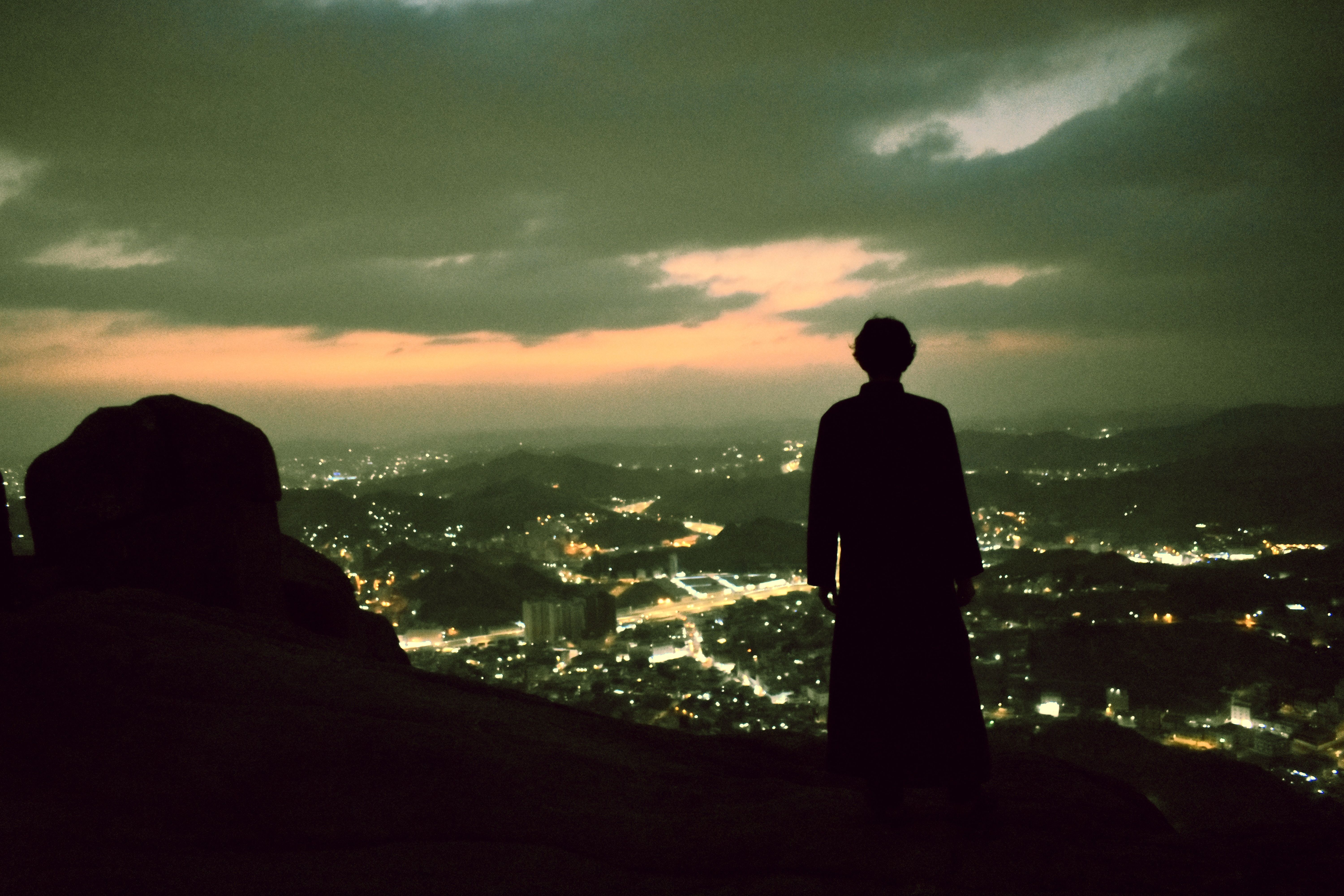 Silhouette of Person Standing on Hilltop over City at Sunset · Free ...
