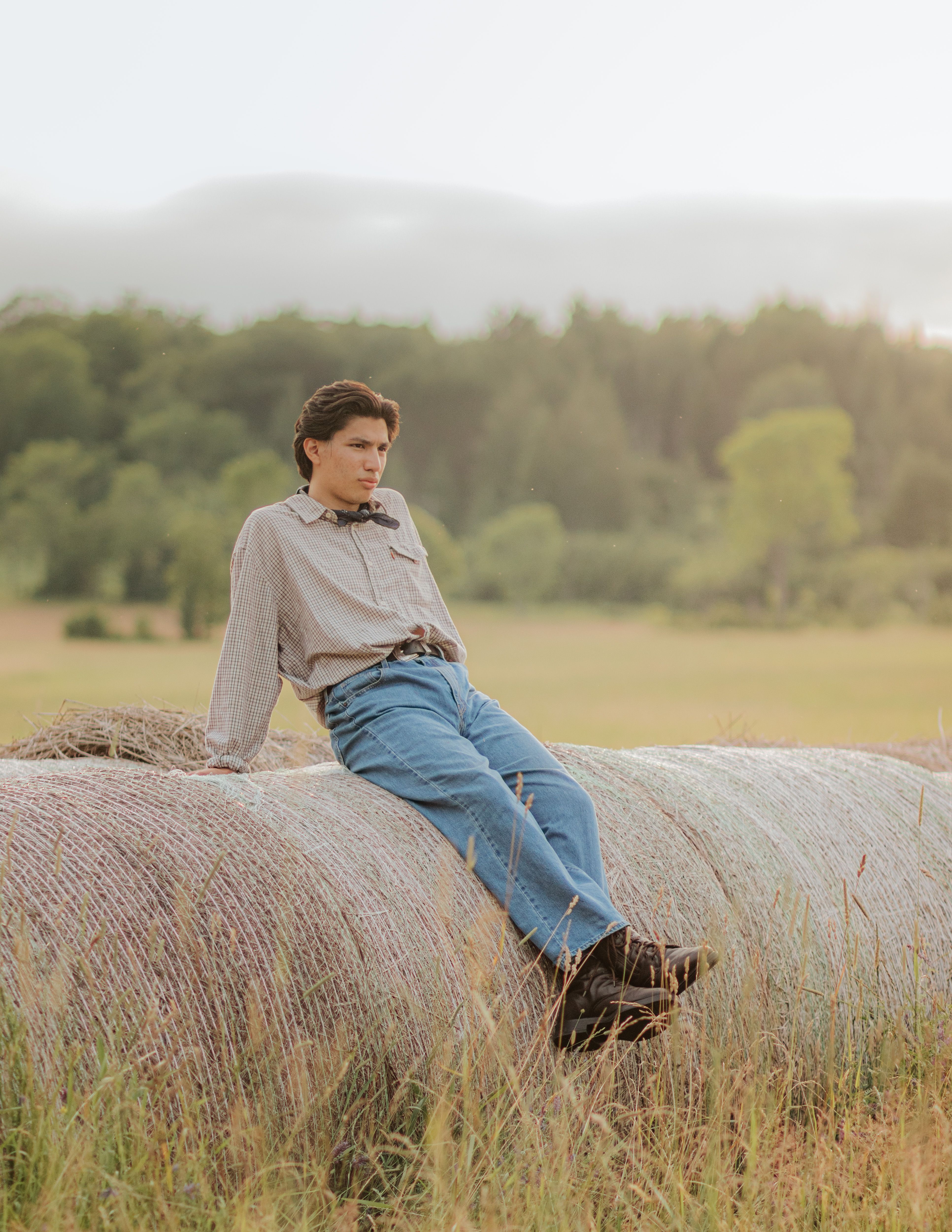 A man sitting on a hay bale in a field · Free Stock Photo