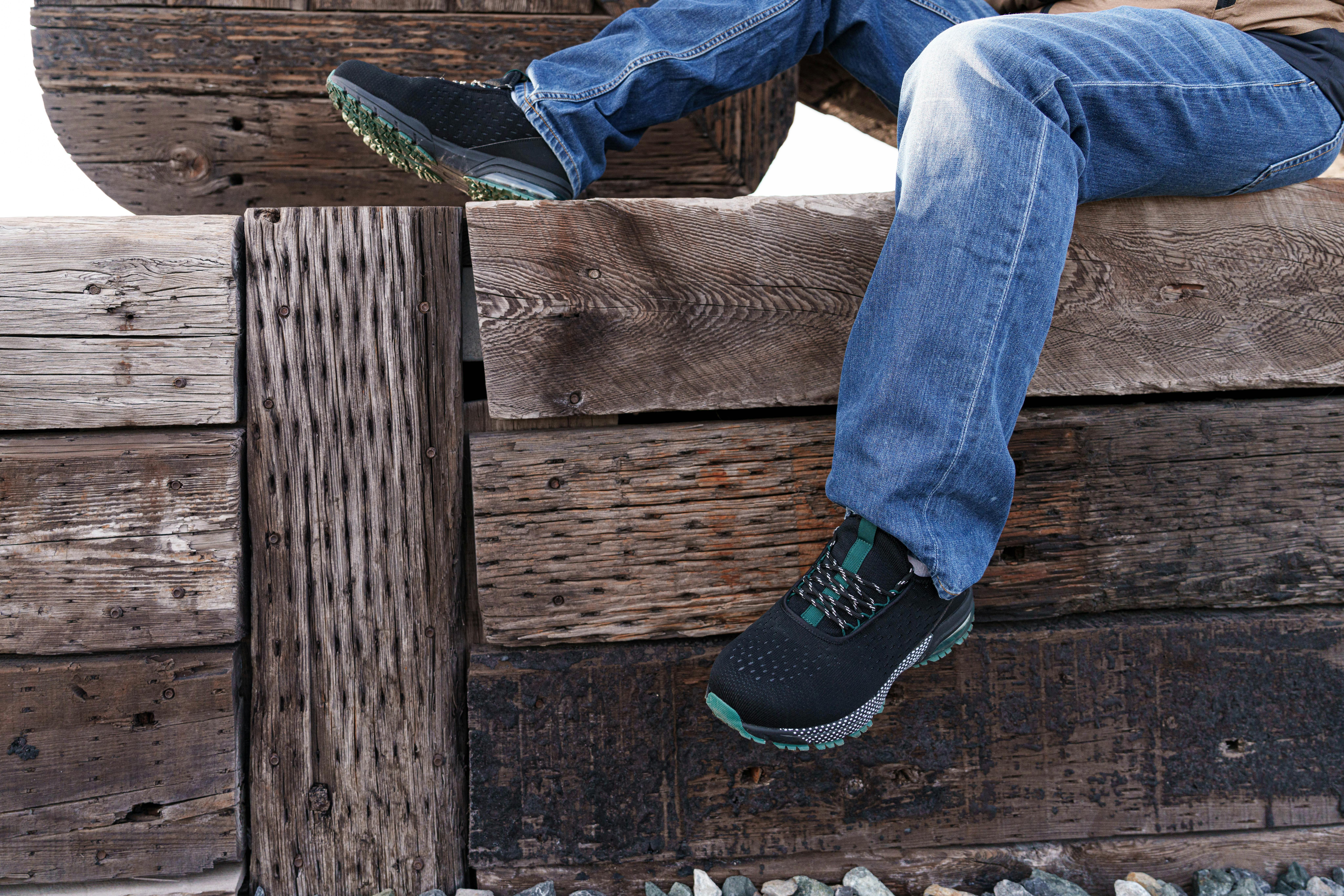 Legs and Shoes of Person Sitting on Wooden Wall · Free Stock Photo