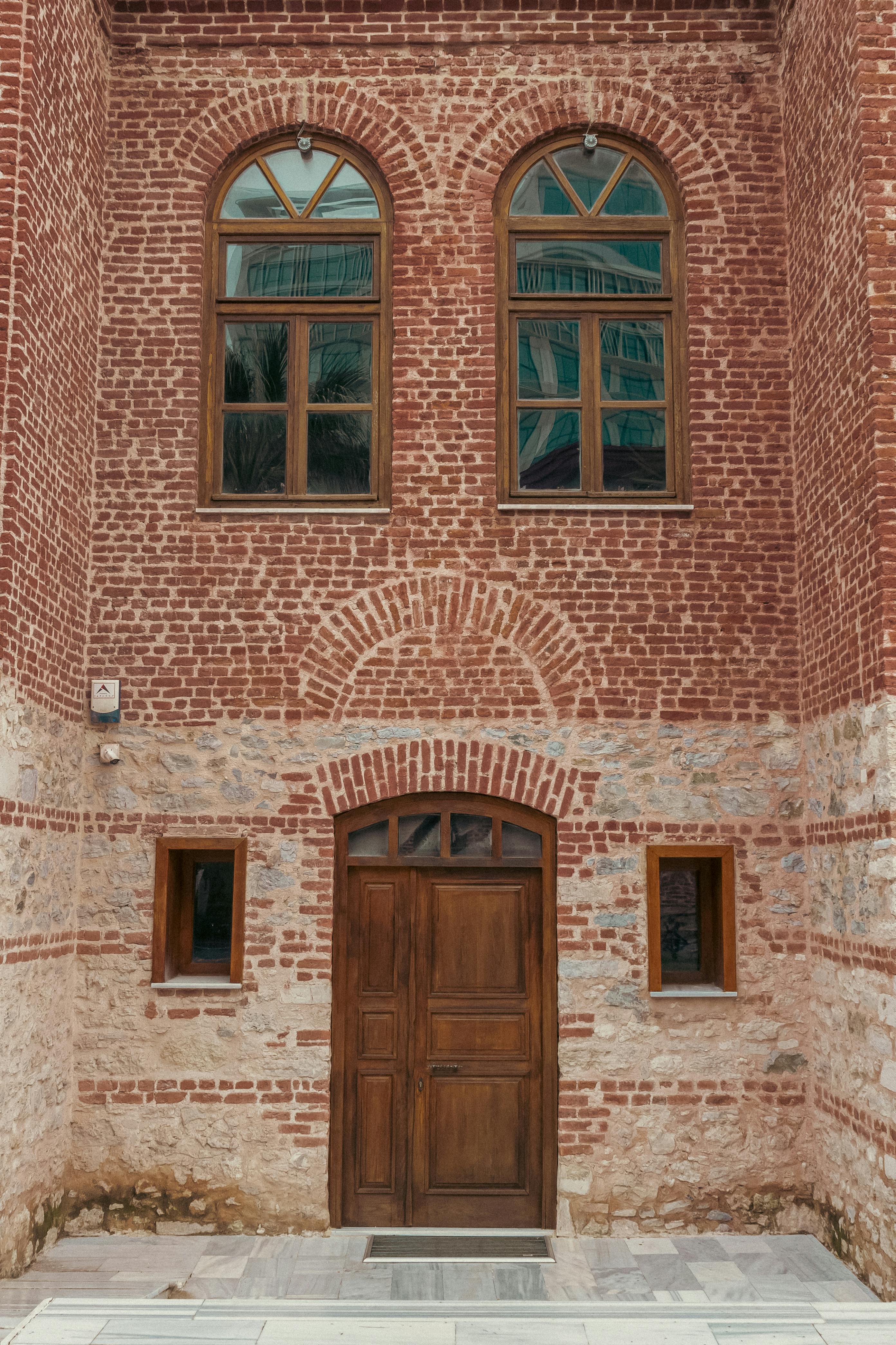 A brick building with a wooden door and windows · Free Stock Photo