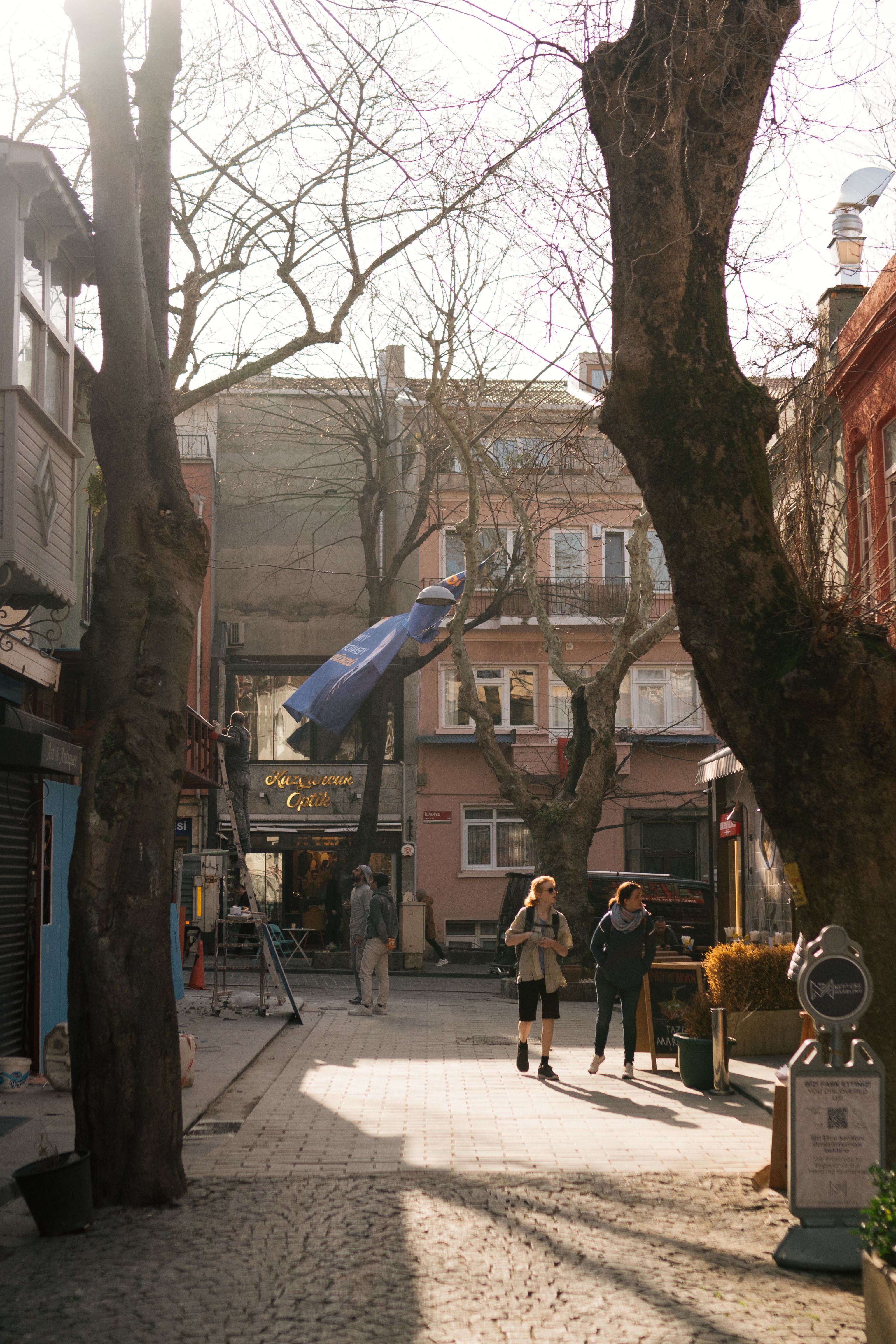 A street with trees and people walking down it · Free Stock Photo