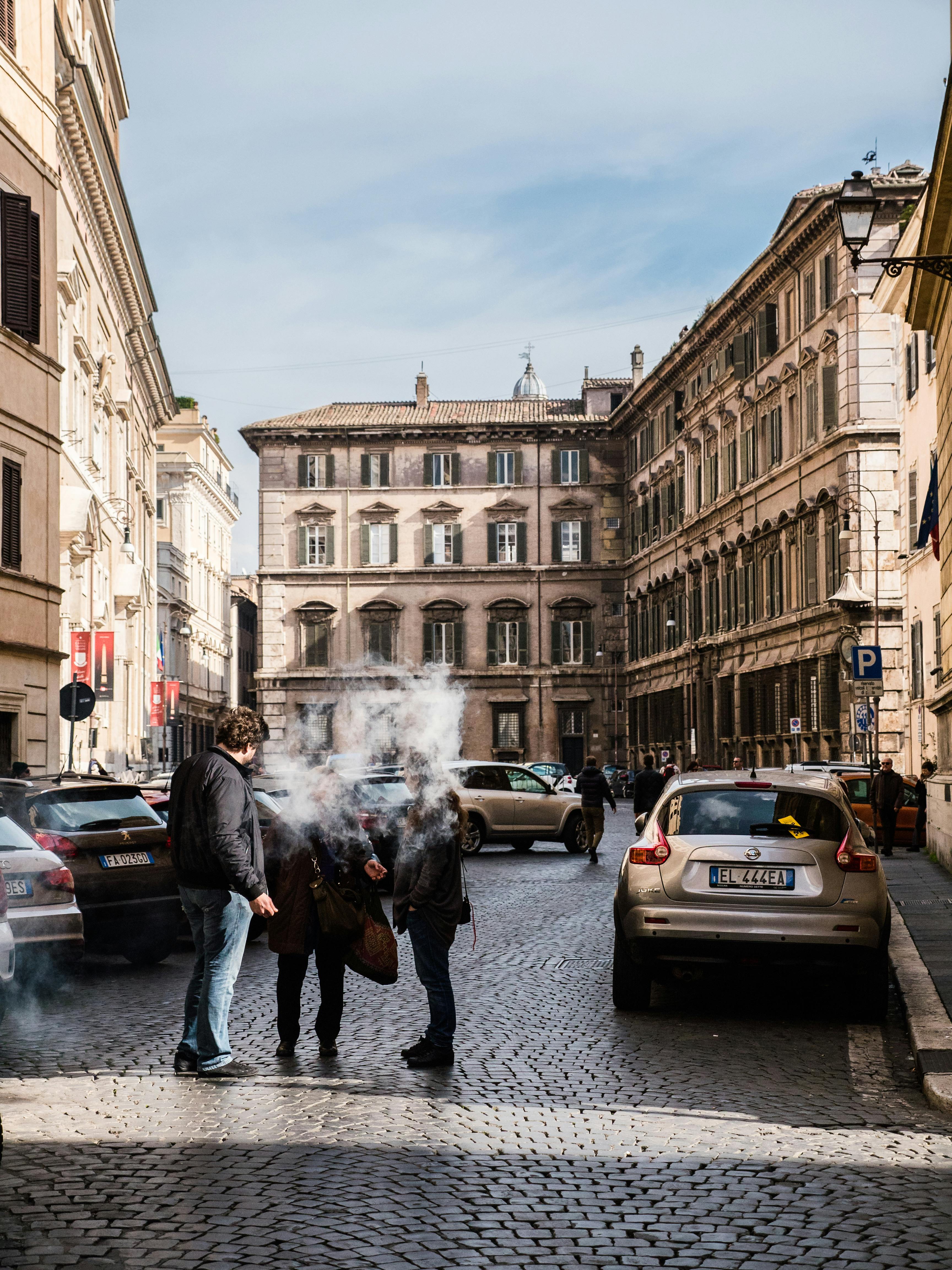 Smoke Floating over Three People Talking on the Street · Free Stock Photo