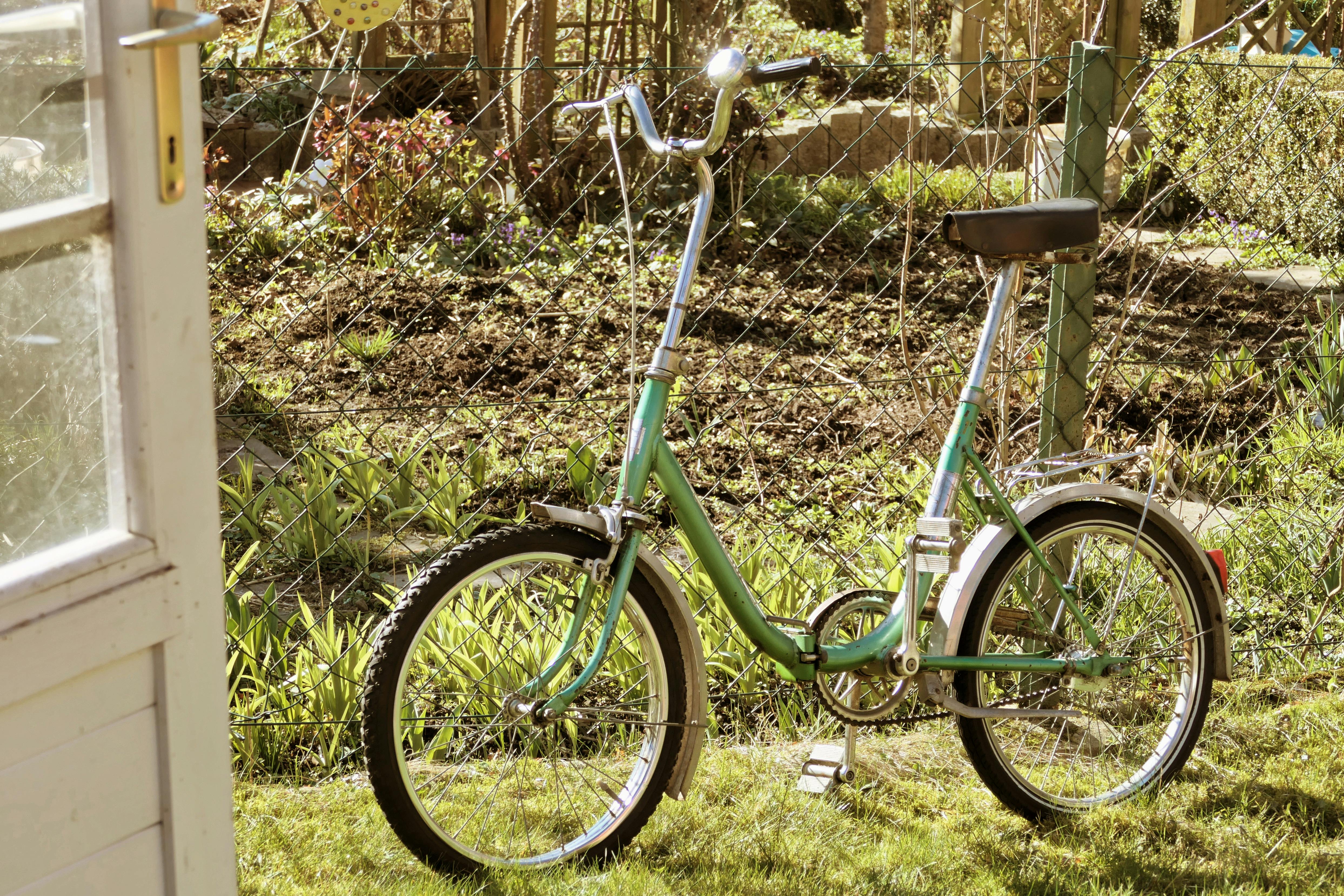 Folding Bicycle Under a Barred Window · Free Stock Photo
