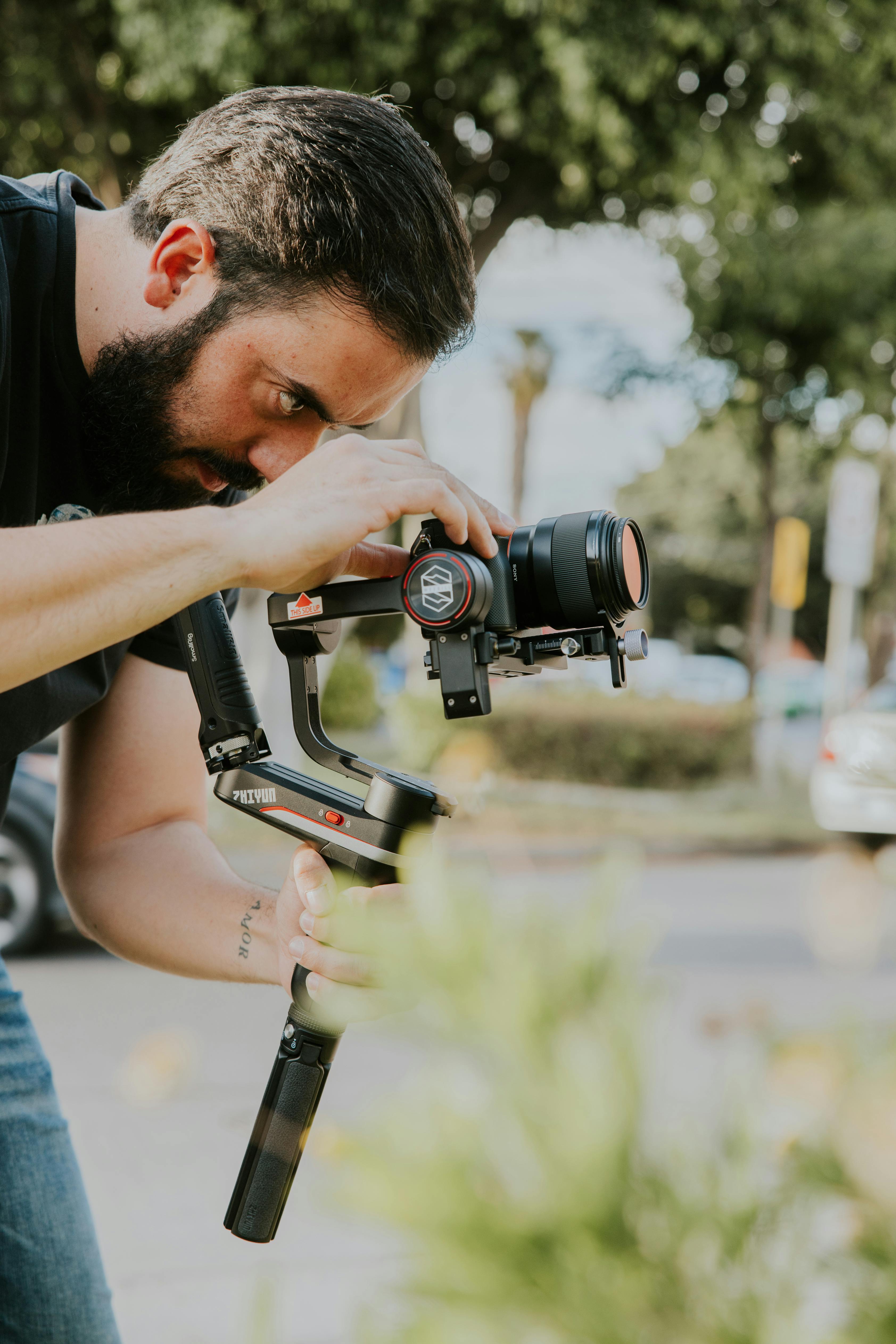 Side View of a Man Using a Camera on a Stabilizer · Free Stock Photo