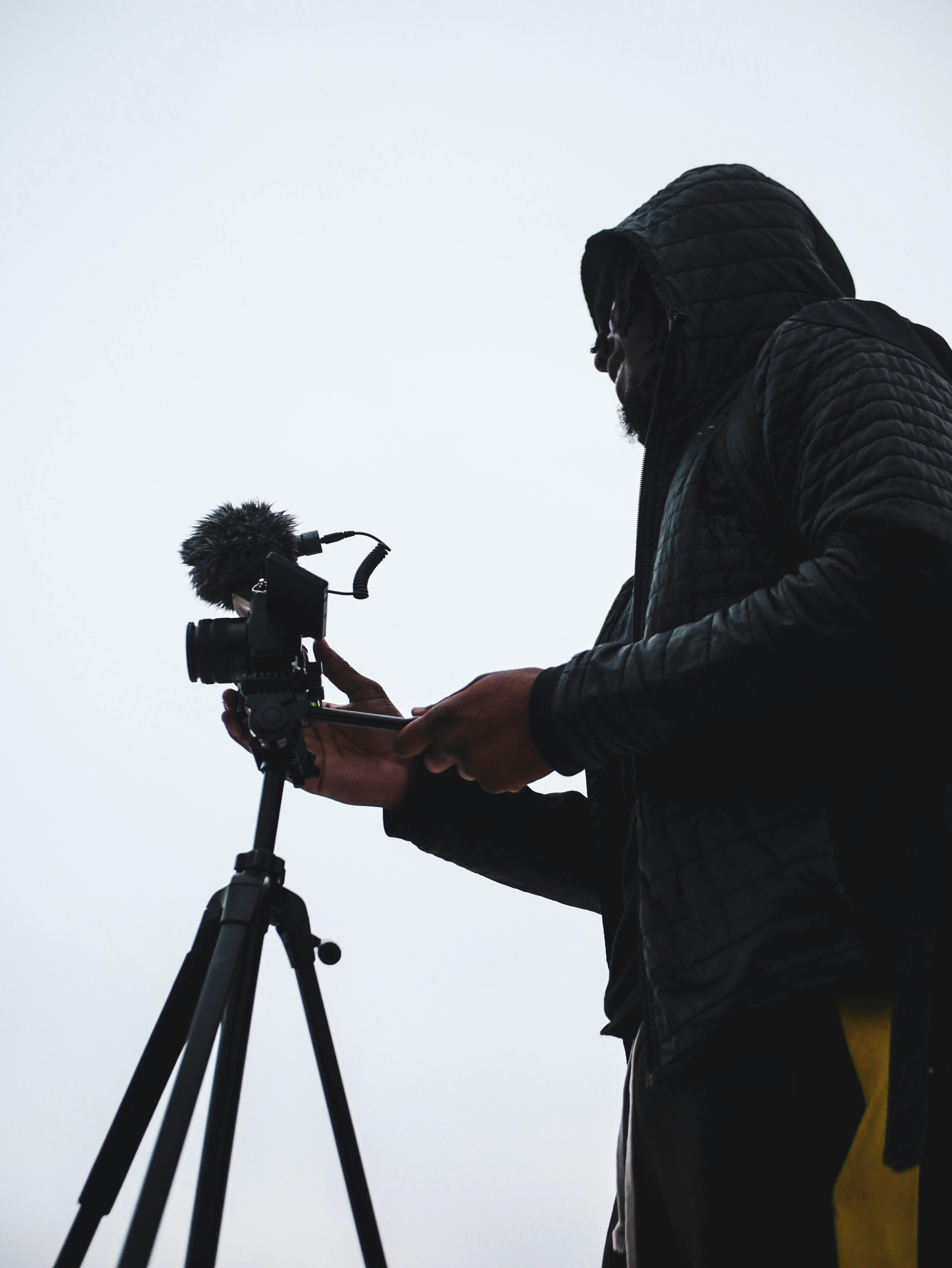 Person Holding Camera on Tripod · Free Stock Photo