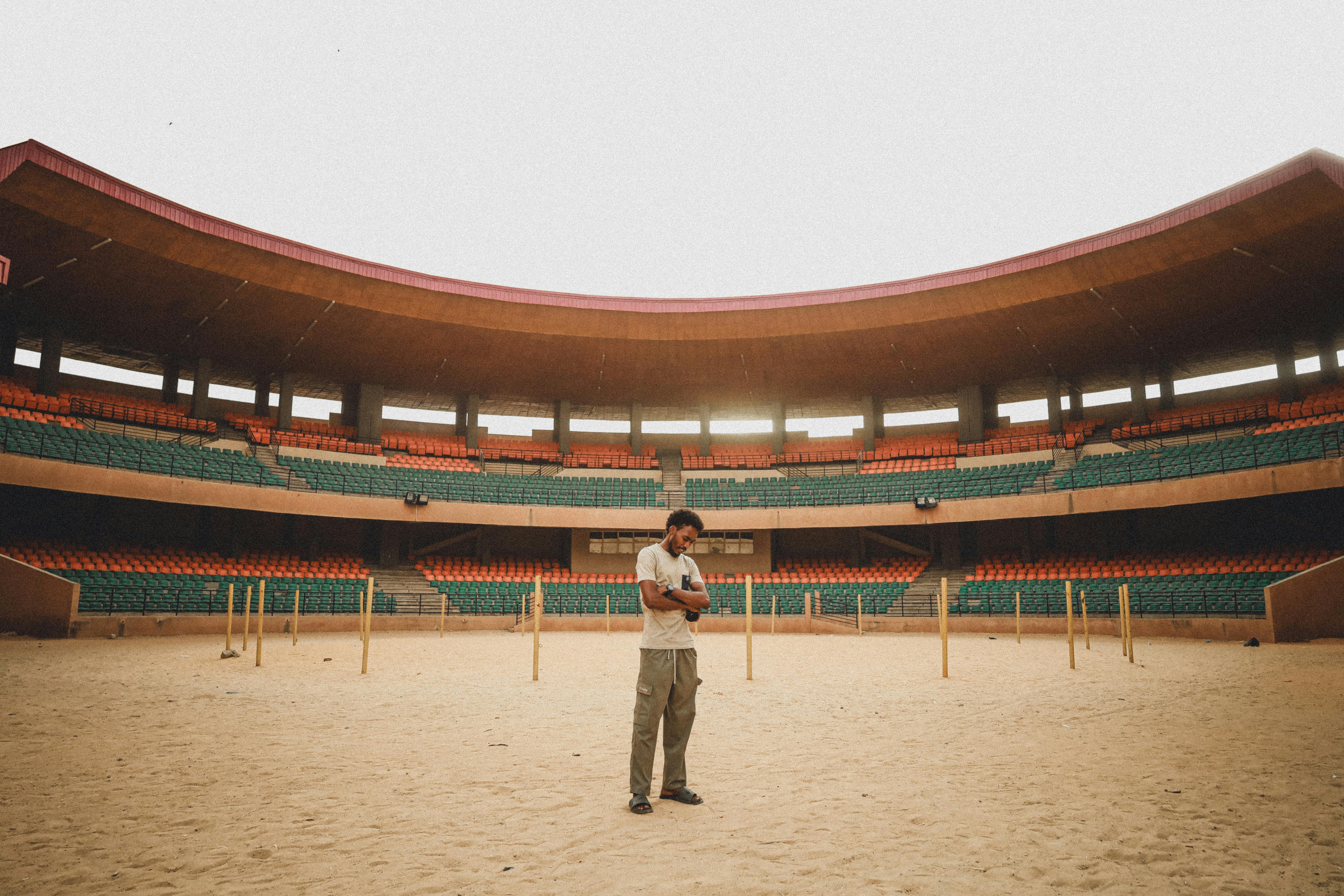 A Man Standing Alone in the Middle of a Sports Arena · Free Stock Photo
