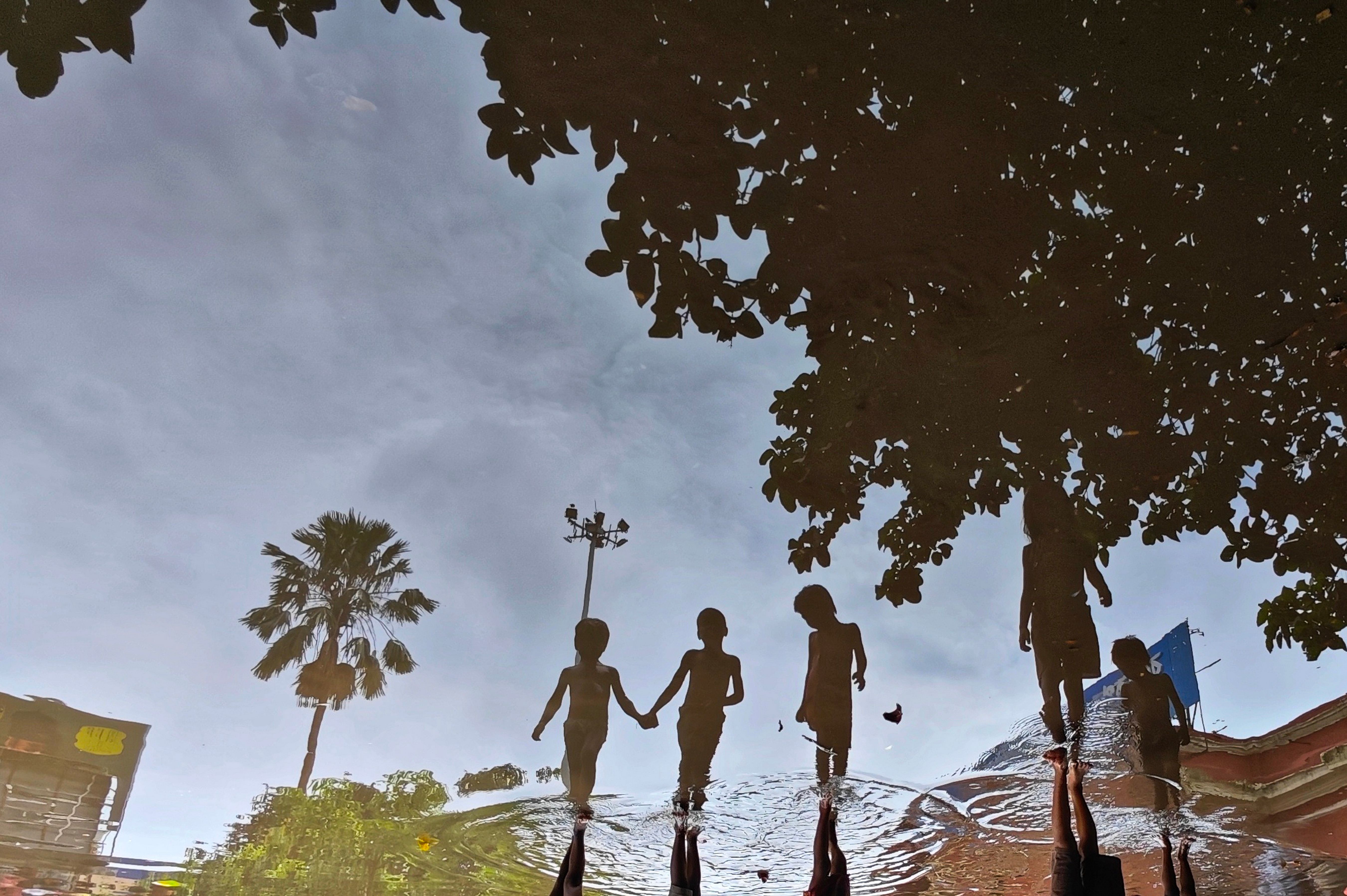 Reflection of Kids Walking on a Street in a Puddle · Free Stock Photo