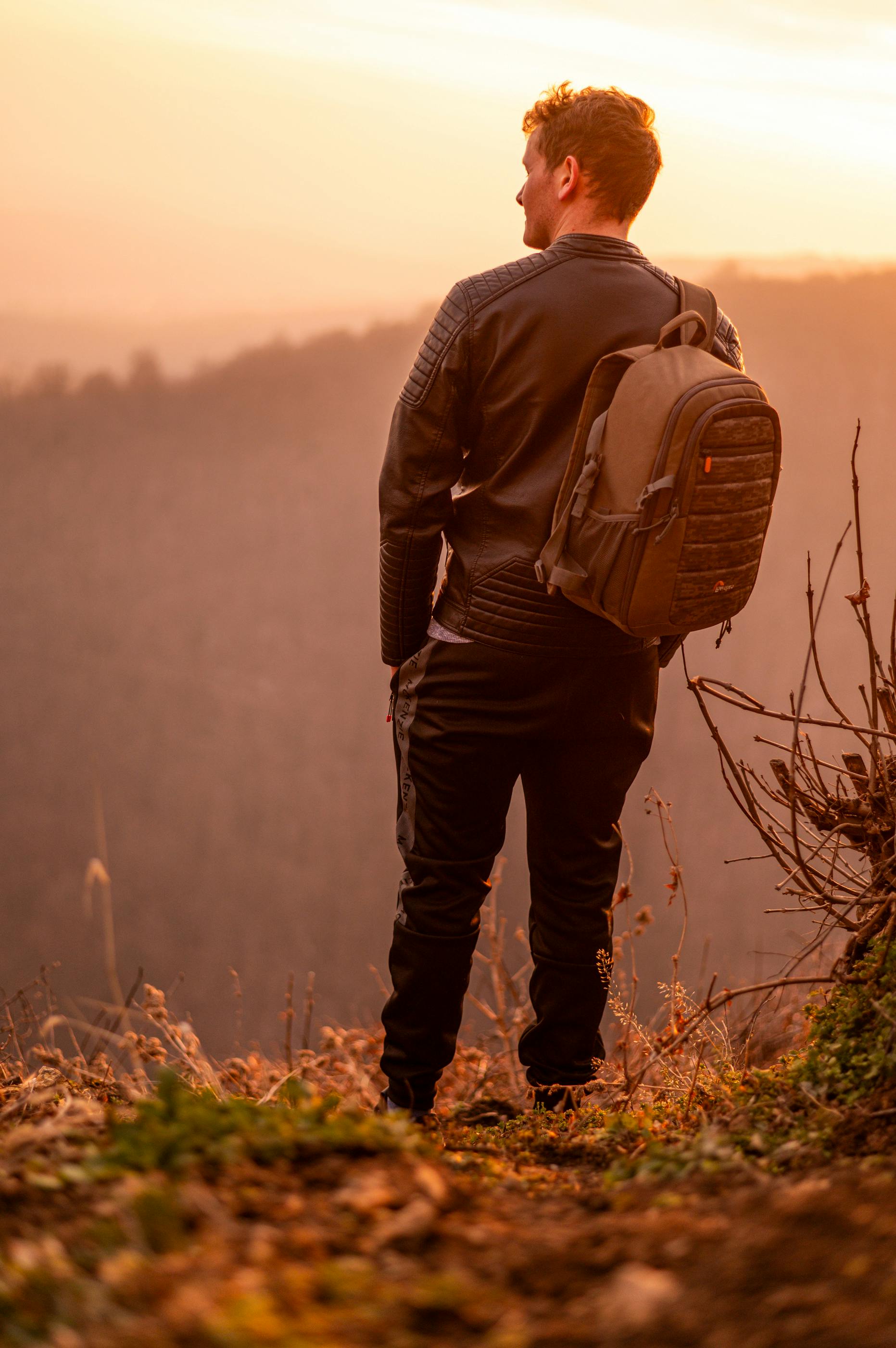 Back View of a Man with a Backpack Standing in Mountains at Sunset ...