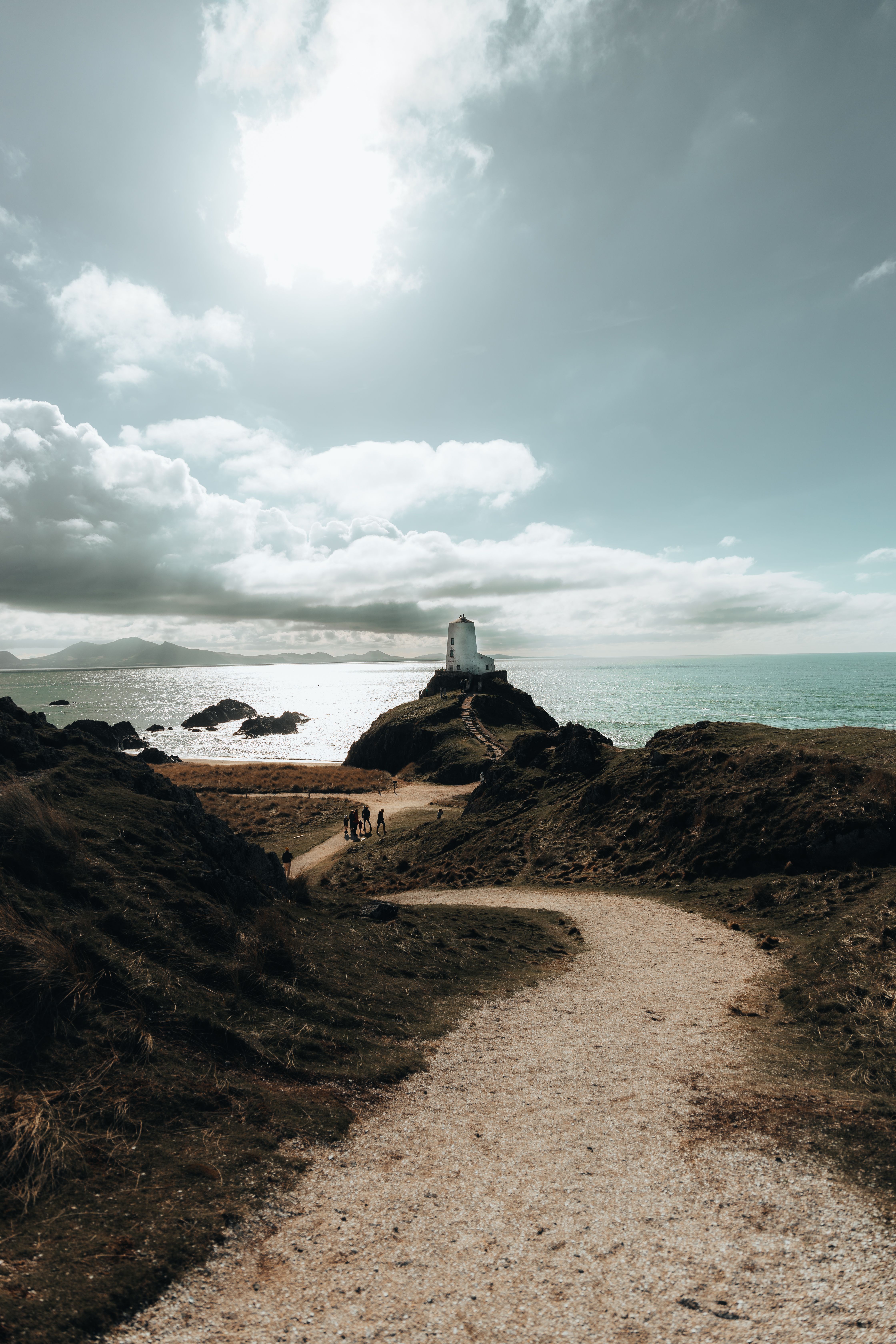 A path leading to a lighthouse on a beach · Free Stock Photo