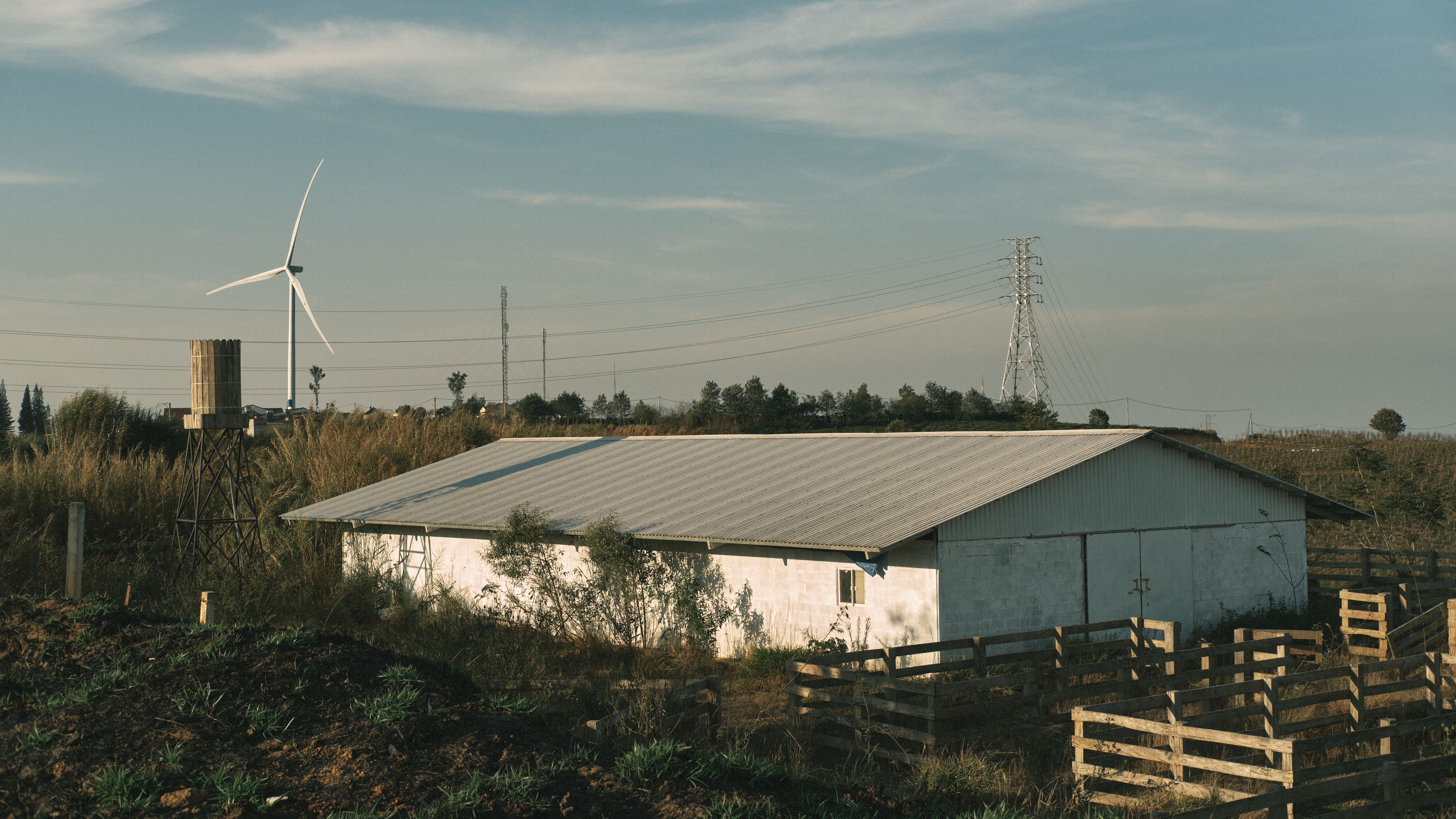 Barn with a Wind Turbine and an Electricity Pylon in the Background ...
