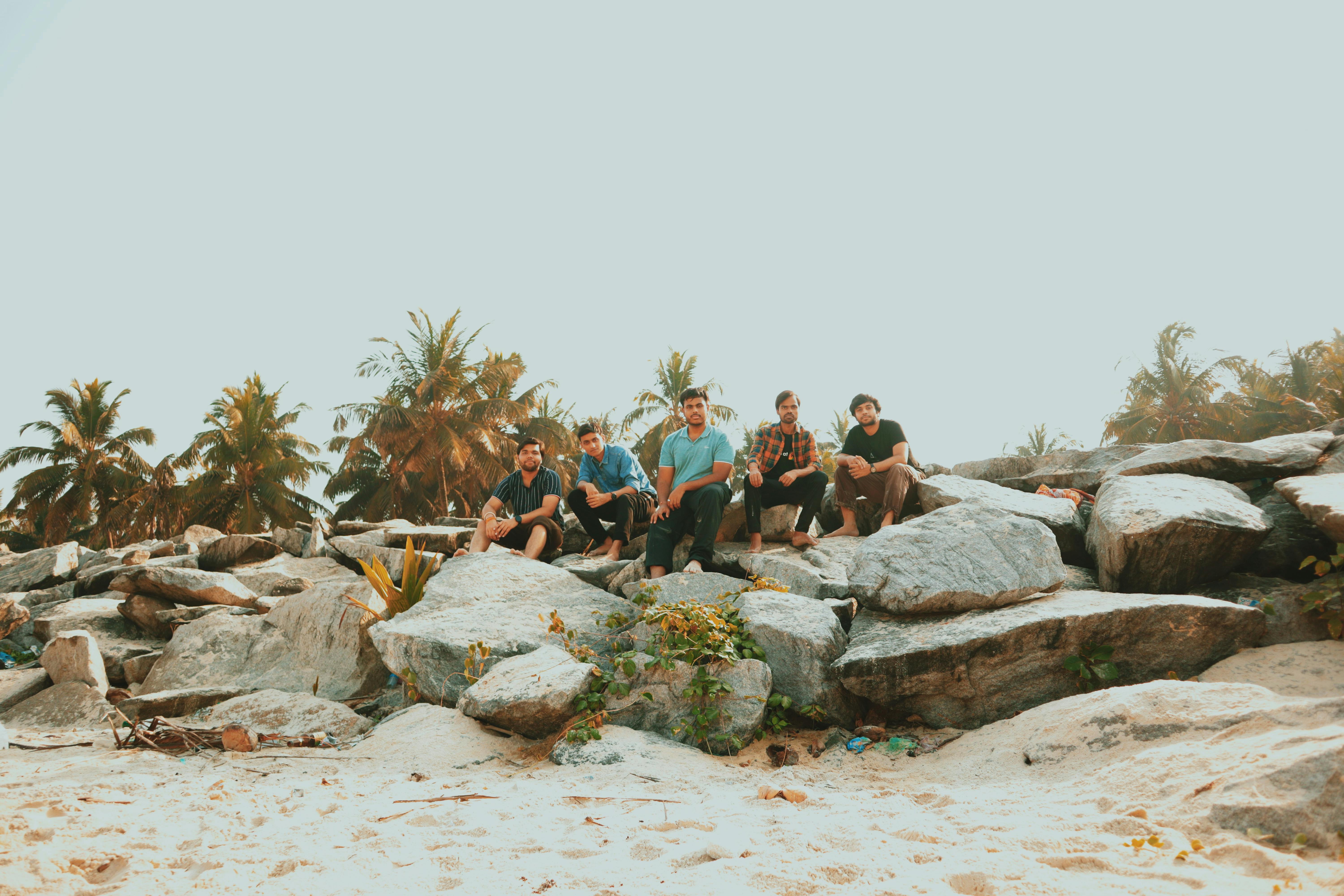 Group of Men Sitting on Rocks on Beach · Free Stock Photo