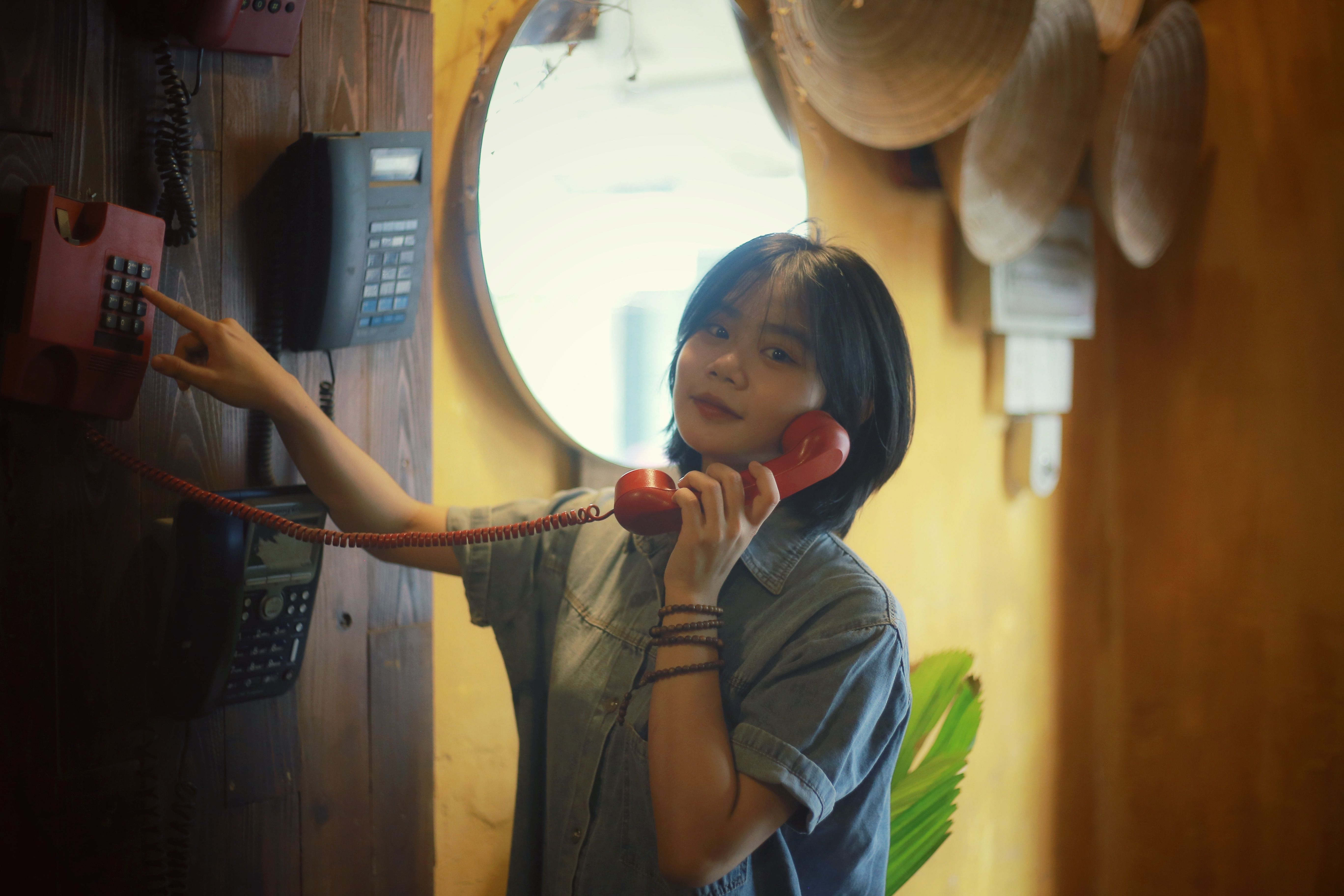 Woman Standing with Vintage Telephones on Wall · Free Stock Photo
