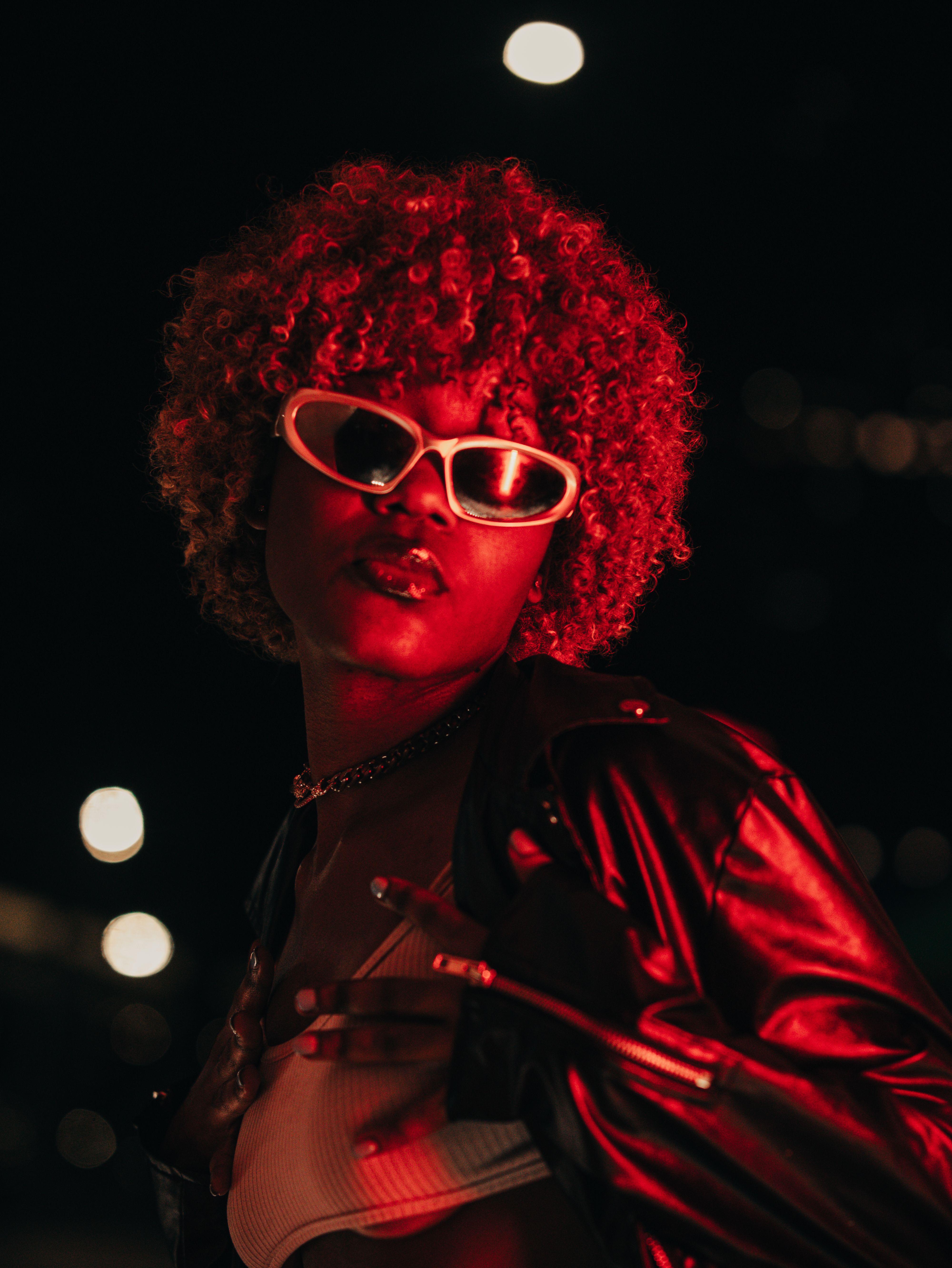 Fashion model with curly hair in red lighting · Free Stock Photo