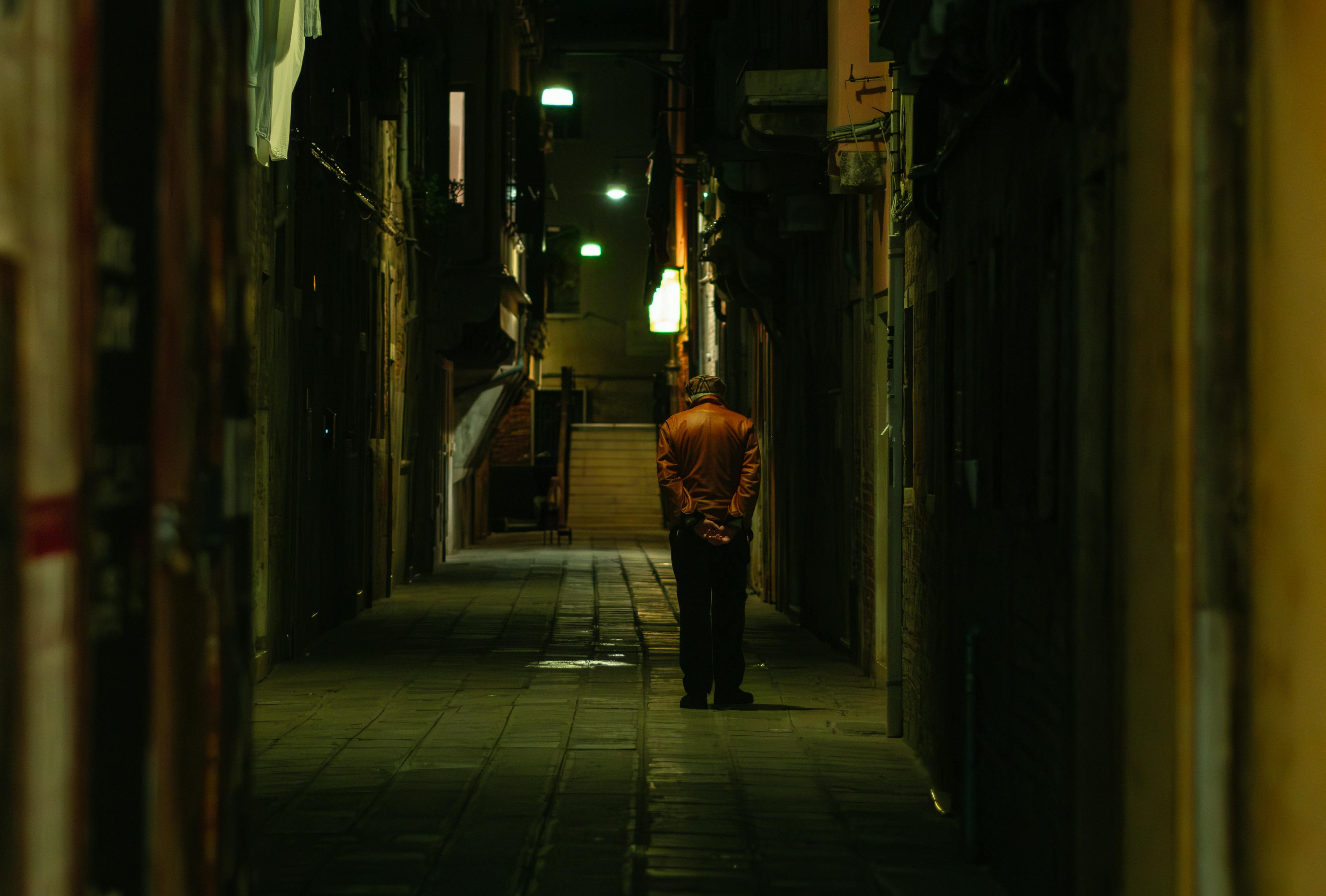 A man is walking down a dark alley at night · Free Stock Photo