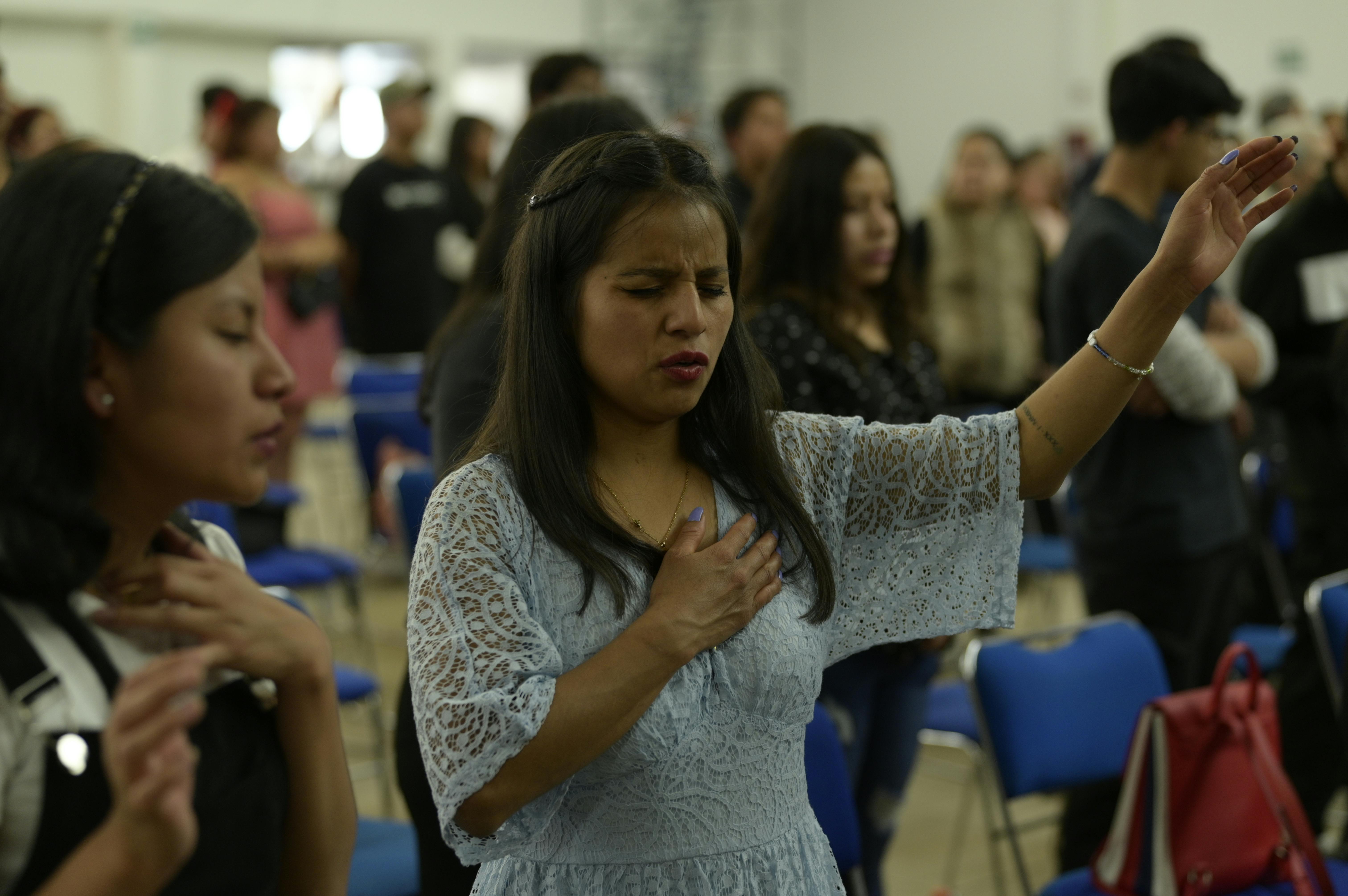 Brunette Woman Standing and Praying at Gathering · Free Stock Photo