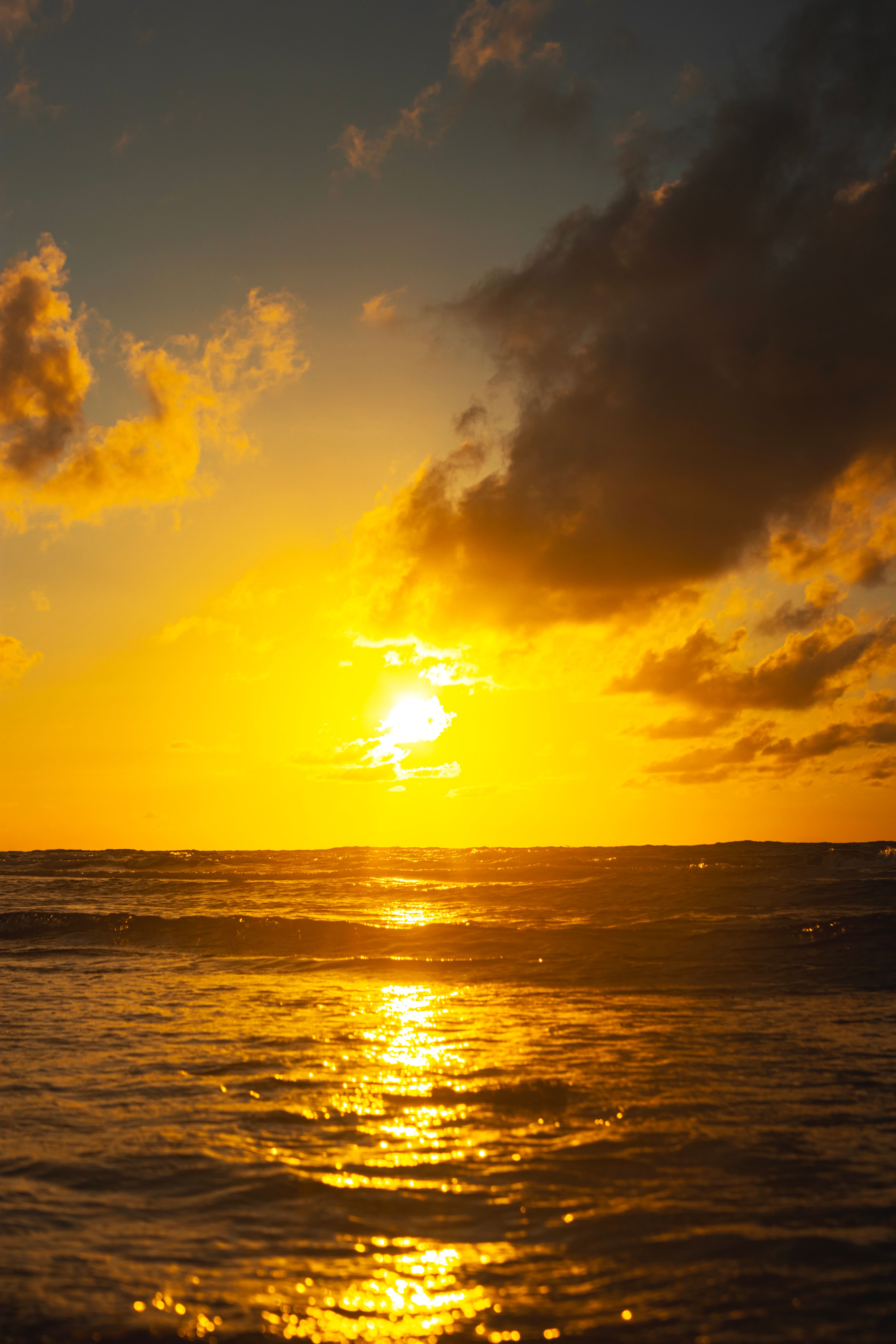 A sunset over the ocean with clouds and water · Free Stock Photo