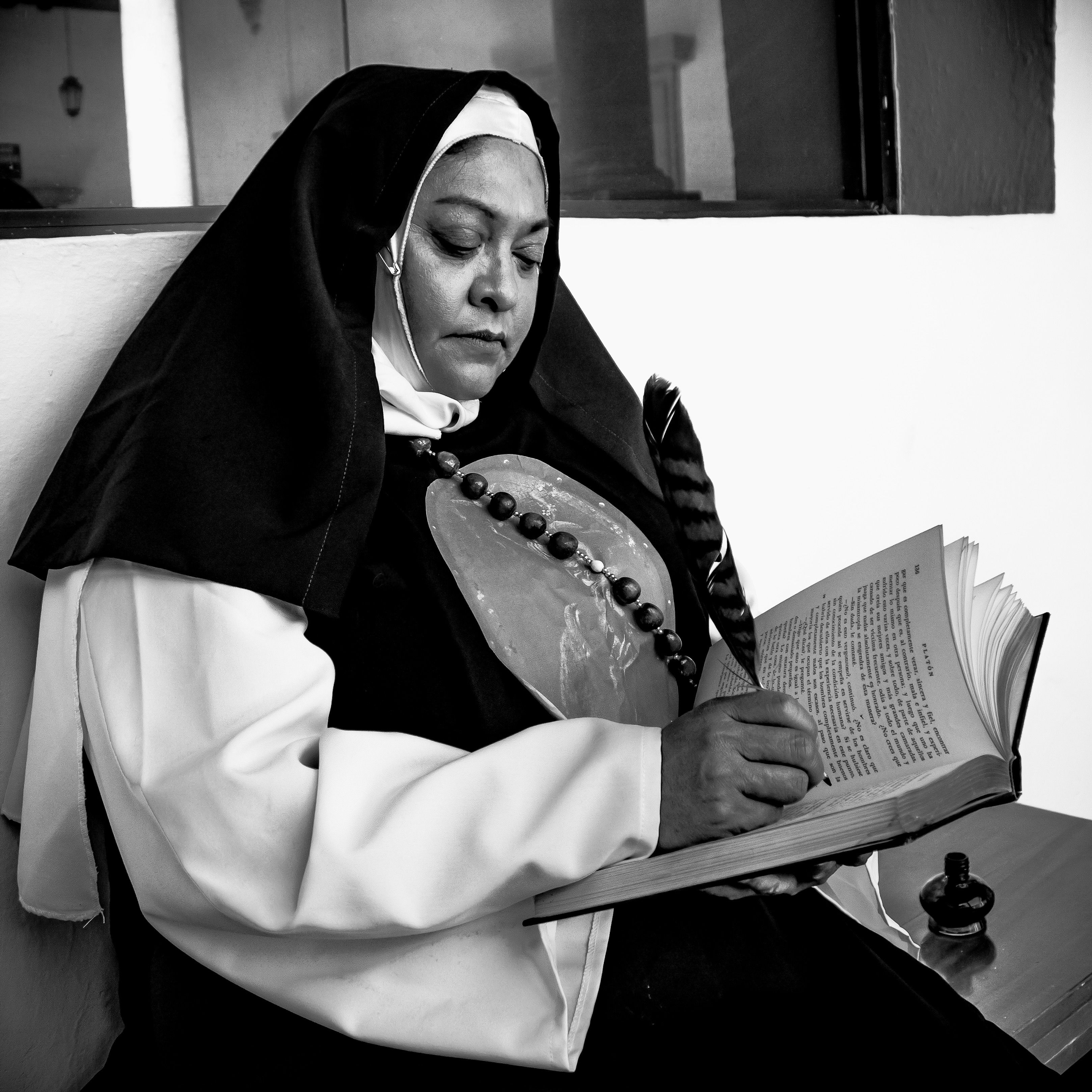 A nun reading a book in a black and white photo · Free Stock Photo