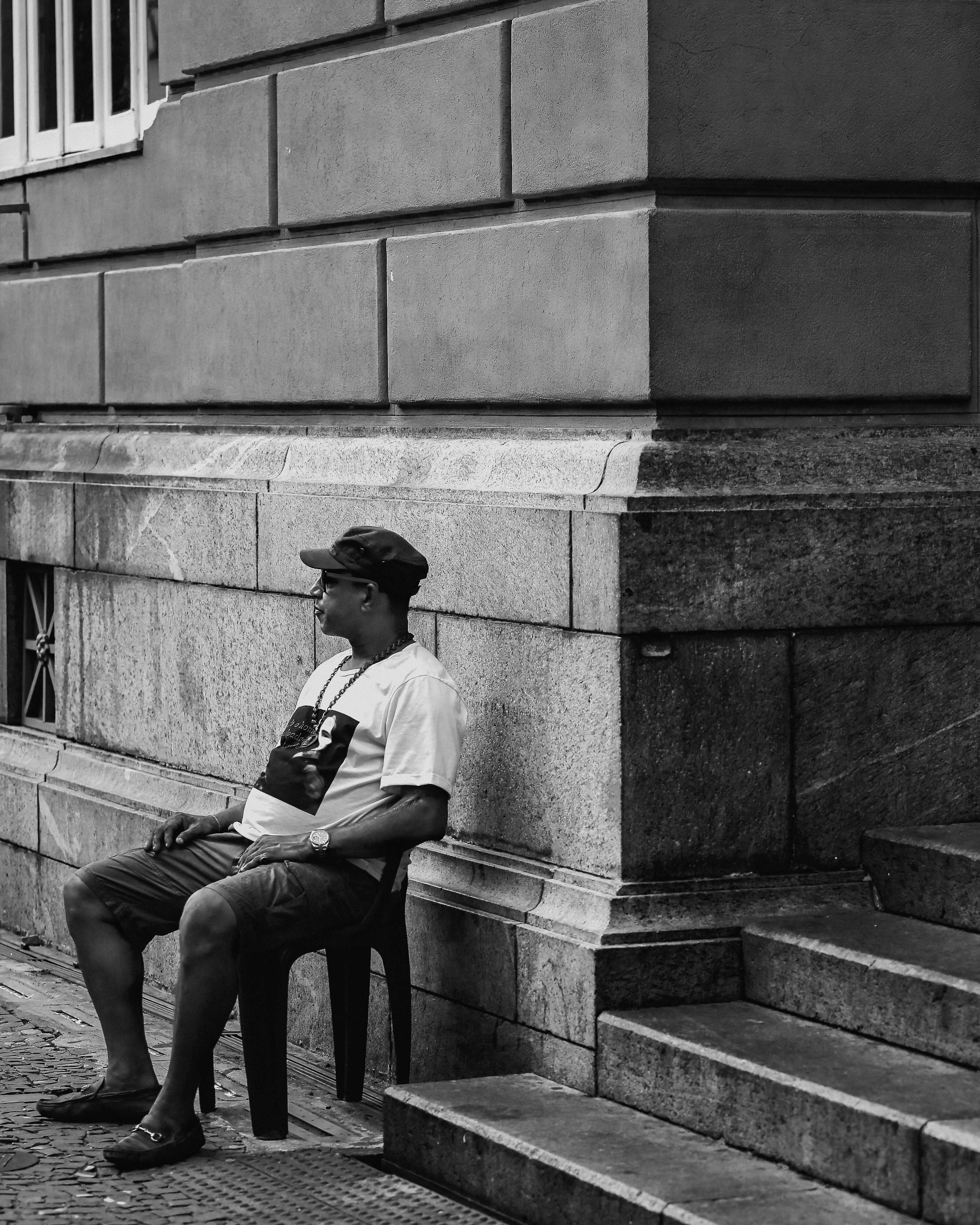 Man in Cap and T-shirt Sitting on Sidewalk · Free Stock Photo