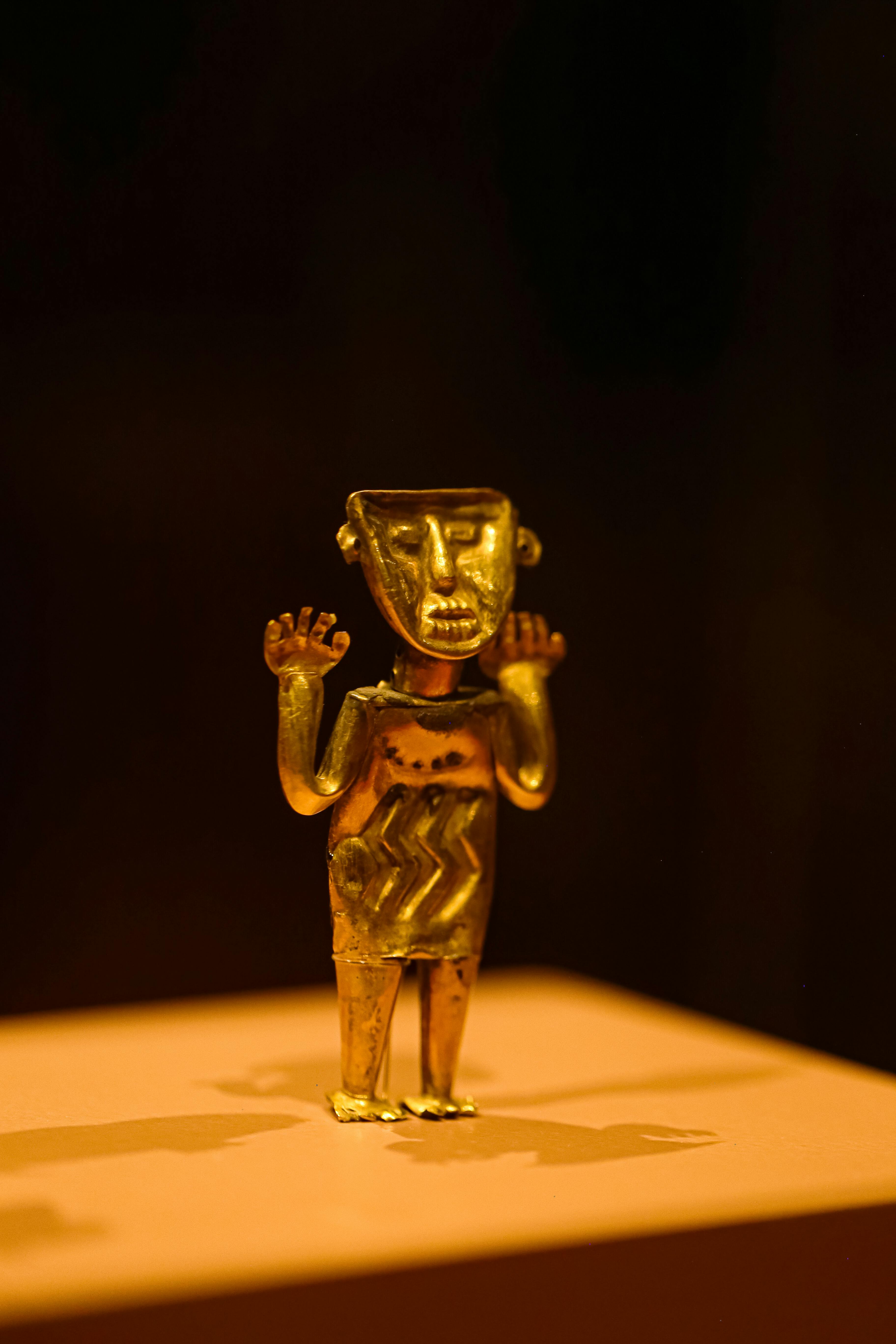 A small gold figurine on display in a museum · Free Stock Photo