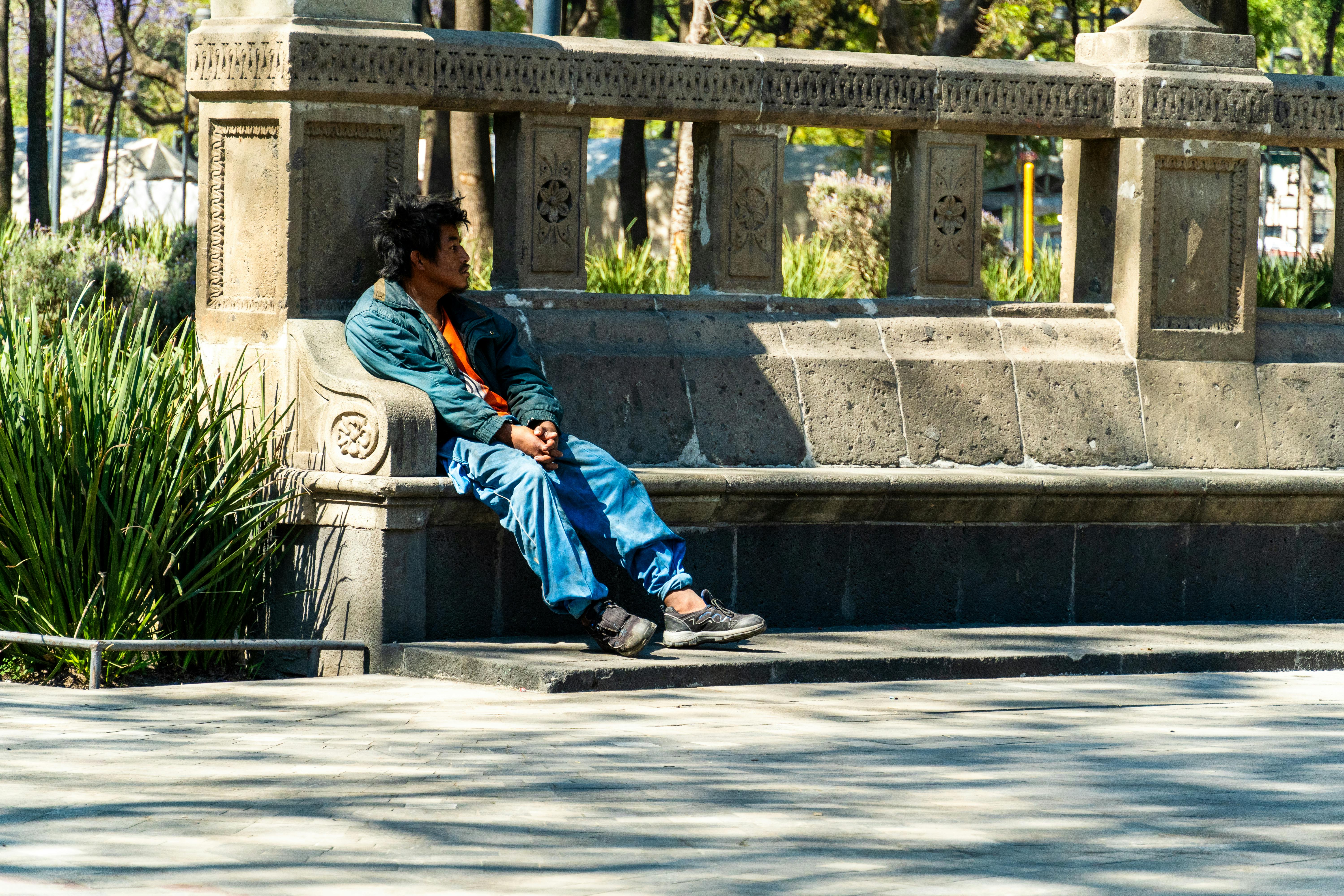 Man Sitting on Stone Bench in a Park · Free Stock Photo