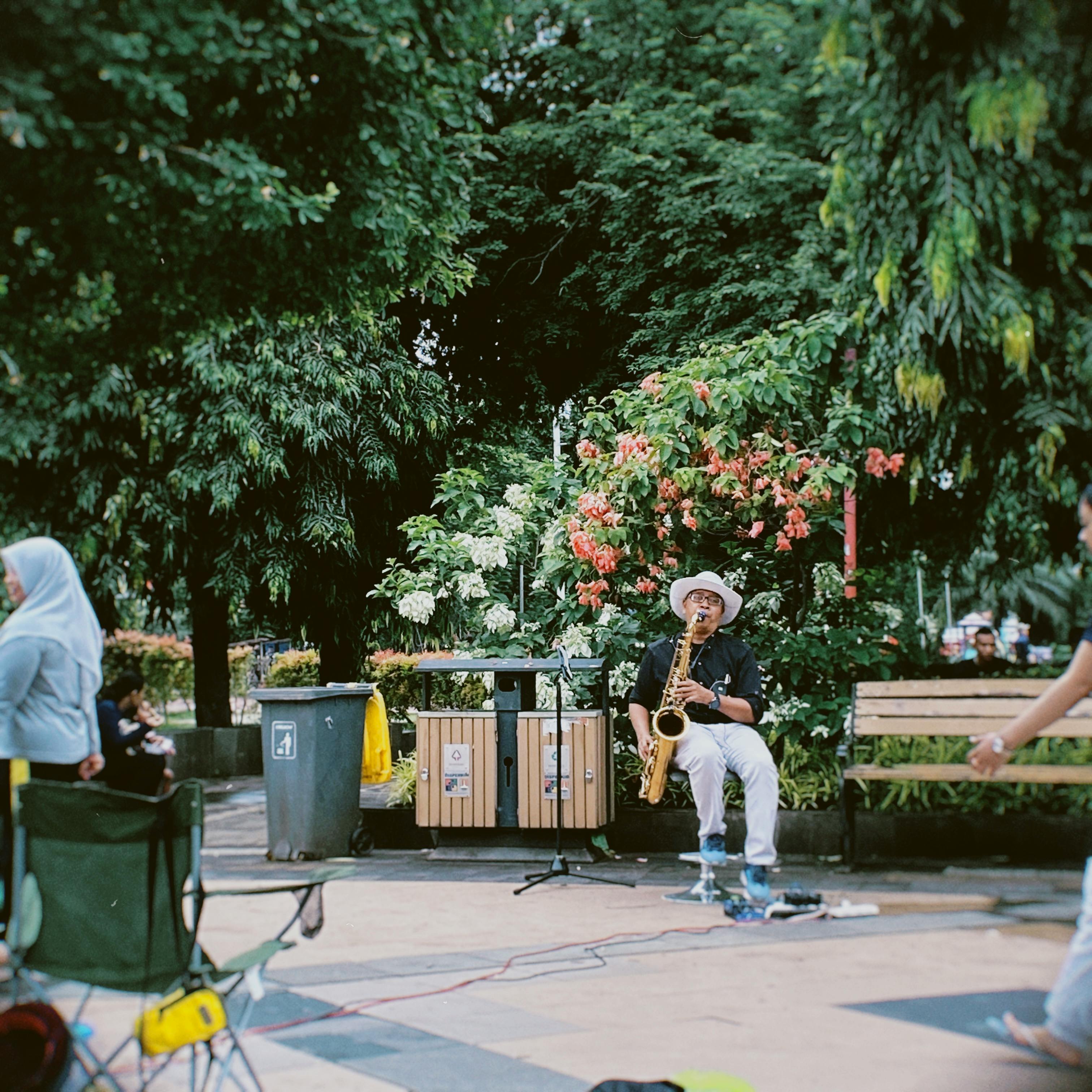 A Man in Black Leather Jacket Sitting on Wooden Bench Playing a ...