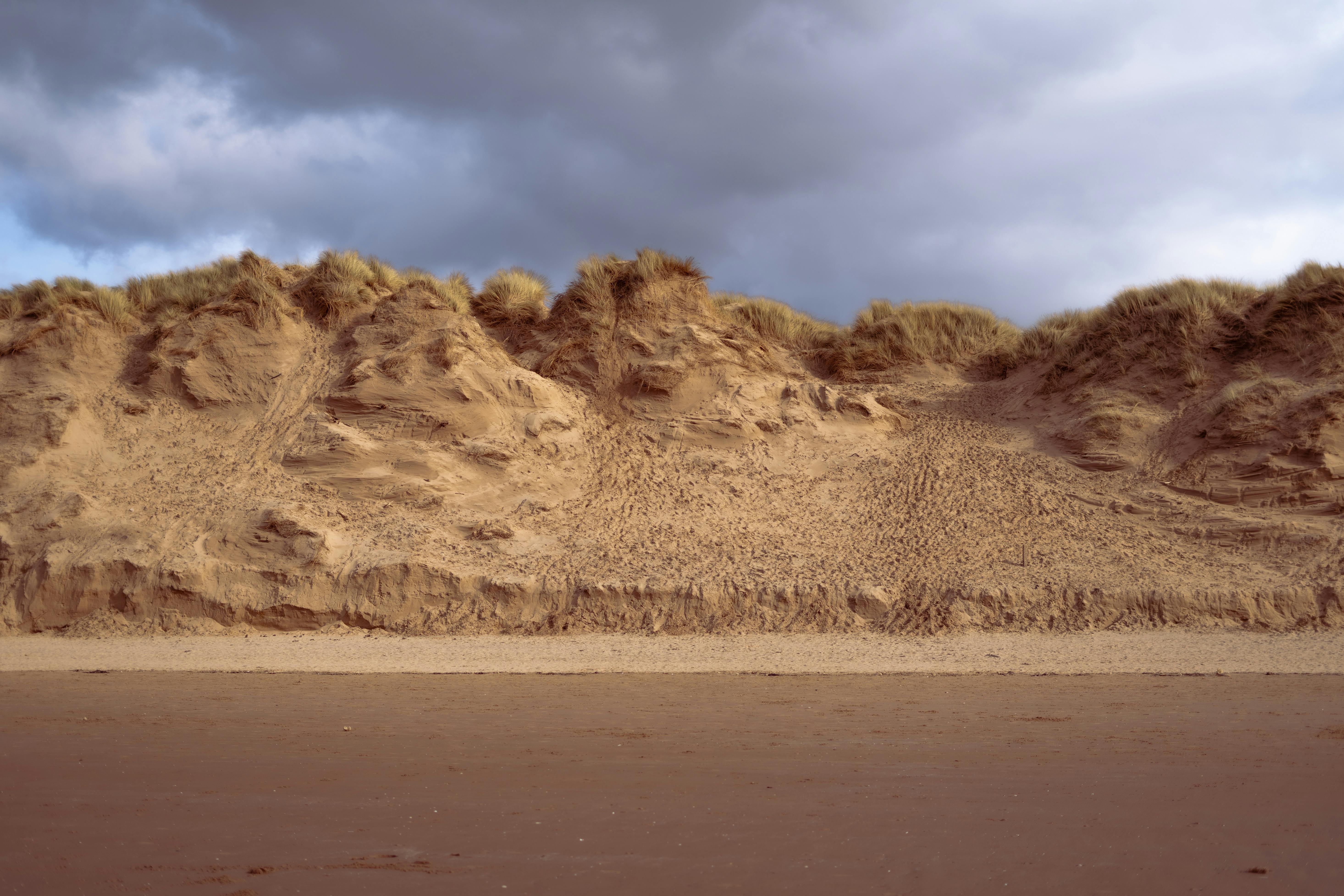 A sandy beach with a large sand dune · Free Stock Photo