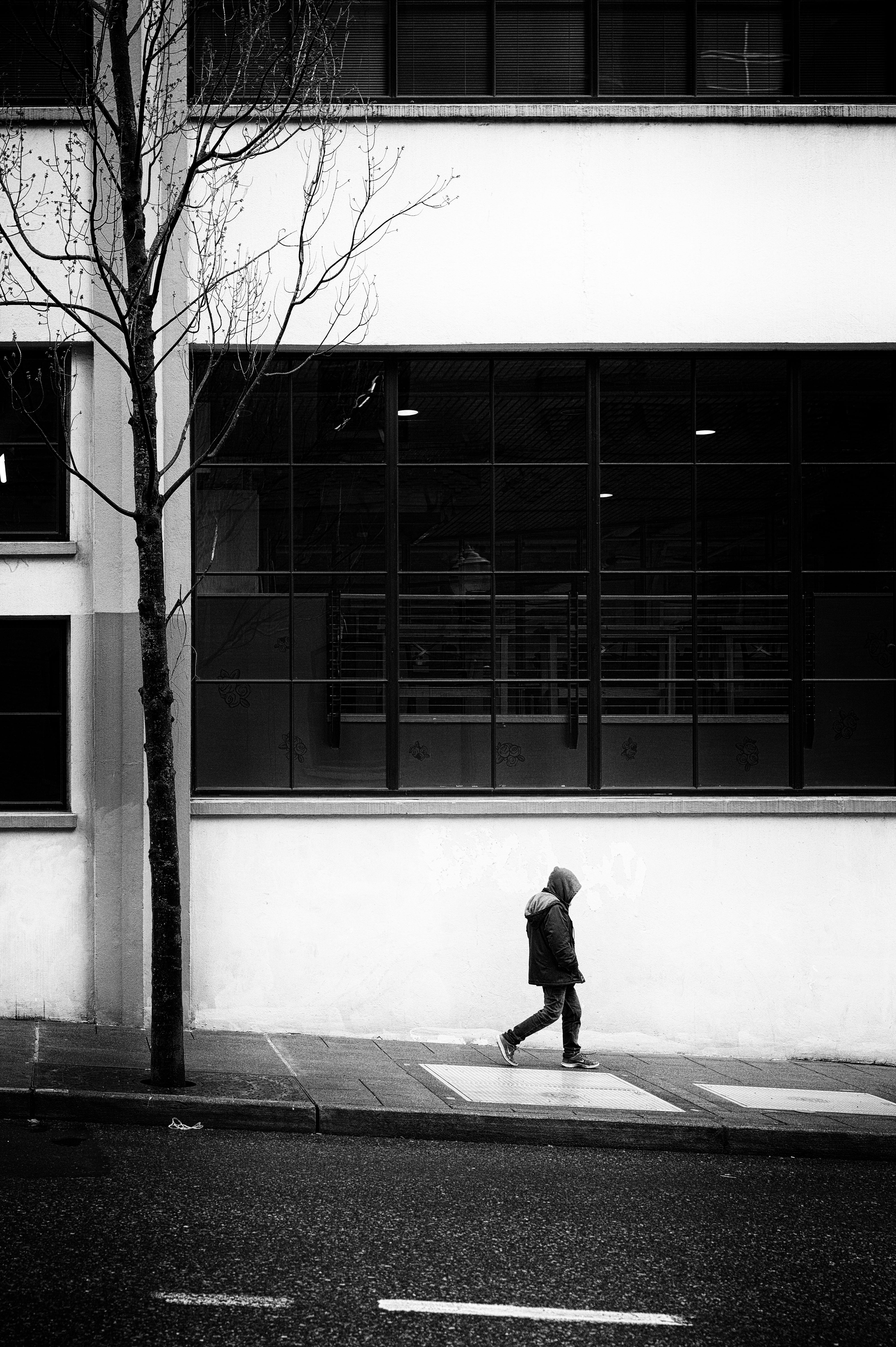 Man Walking near Building Wall in Black and White · Free Stock Photo