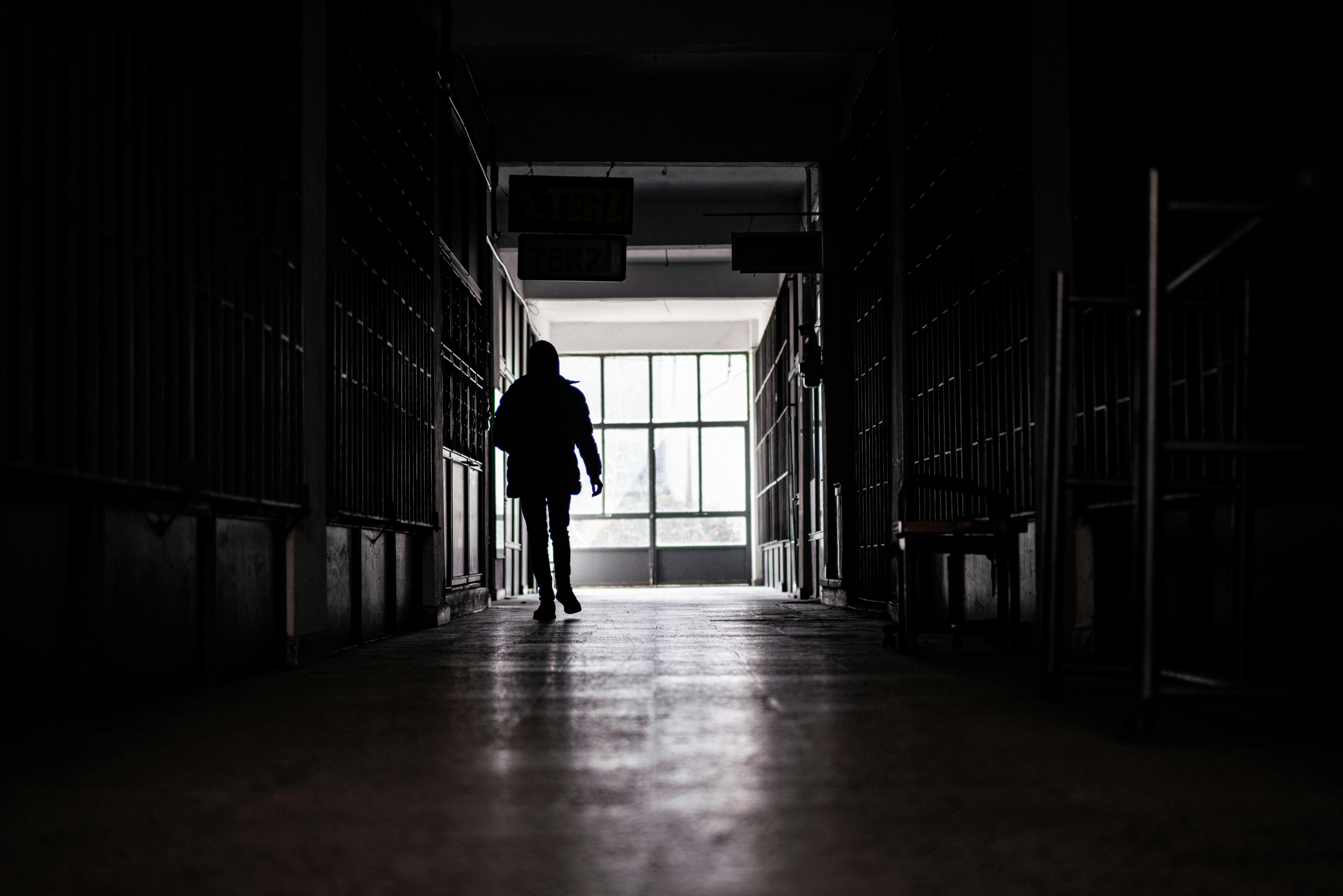 A man walking down a hallway in a dark building · Free Stock Photo