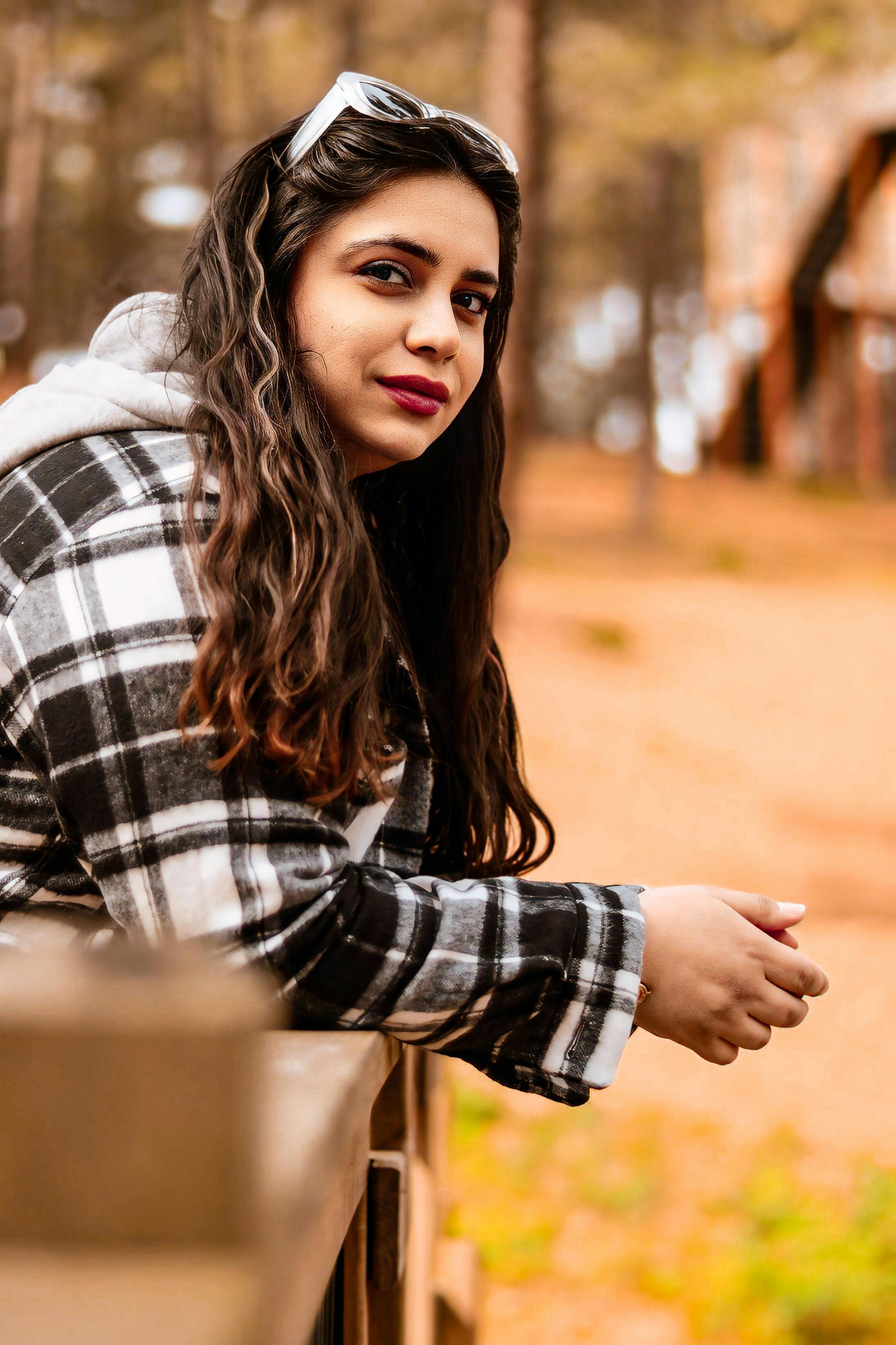 Woman in Check Shirt Leaning on Wooden Railing · Free Stock Photo