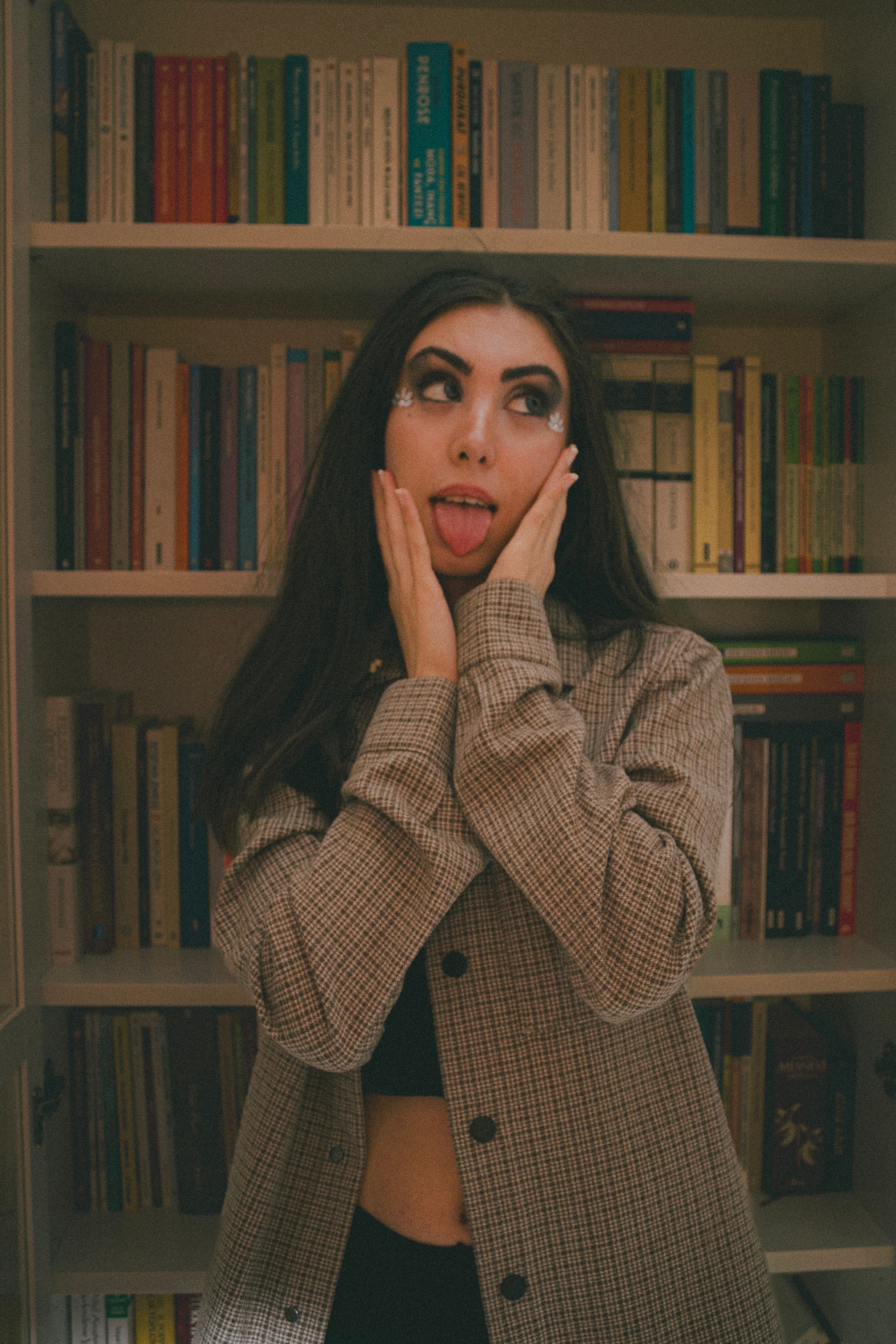 Young Woman Standing in Front of a Bookcase in a Library · Free Stock Photo