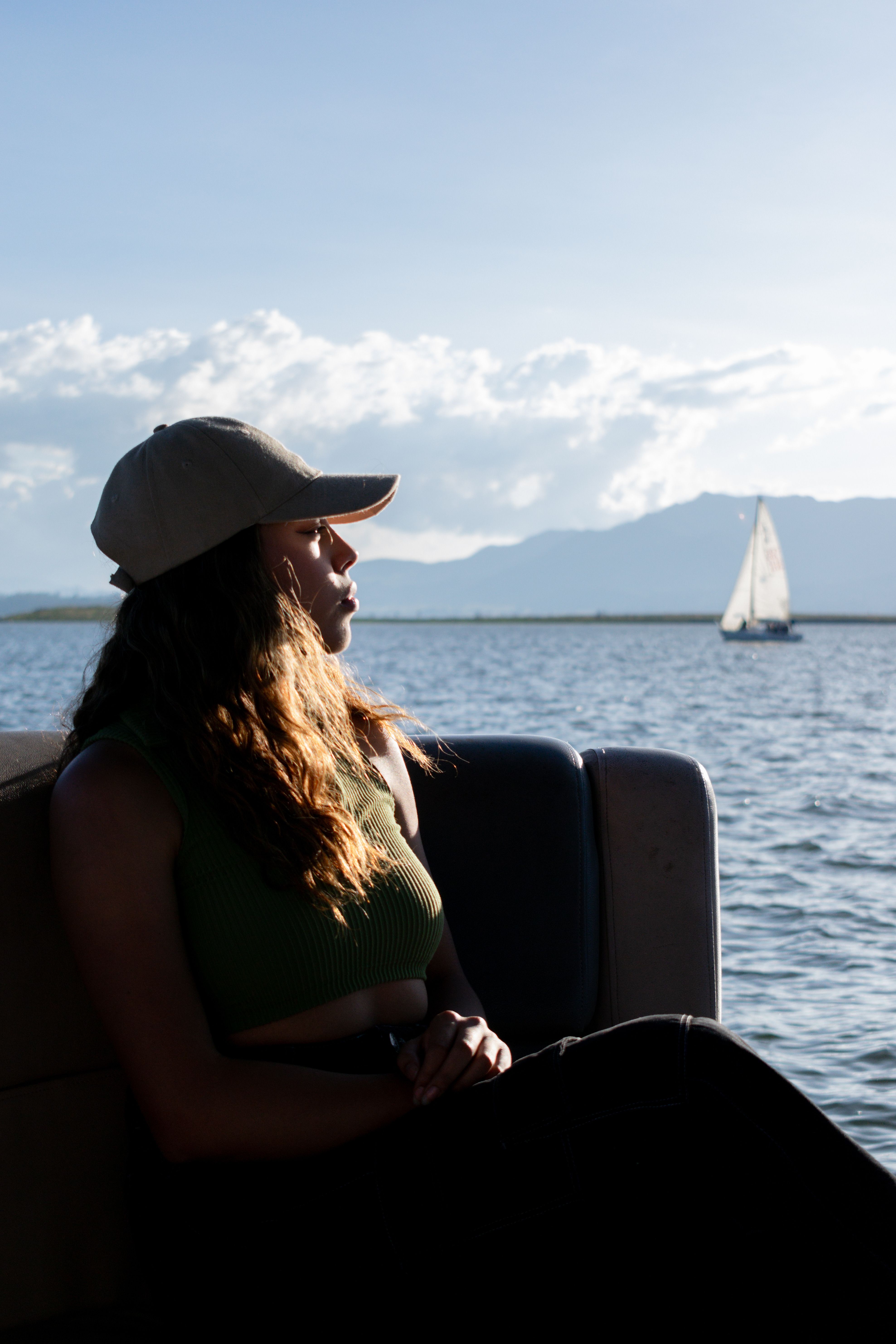 Woman in Cap Sitting on Sea Shore · Free Stock Photo