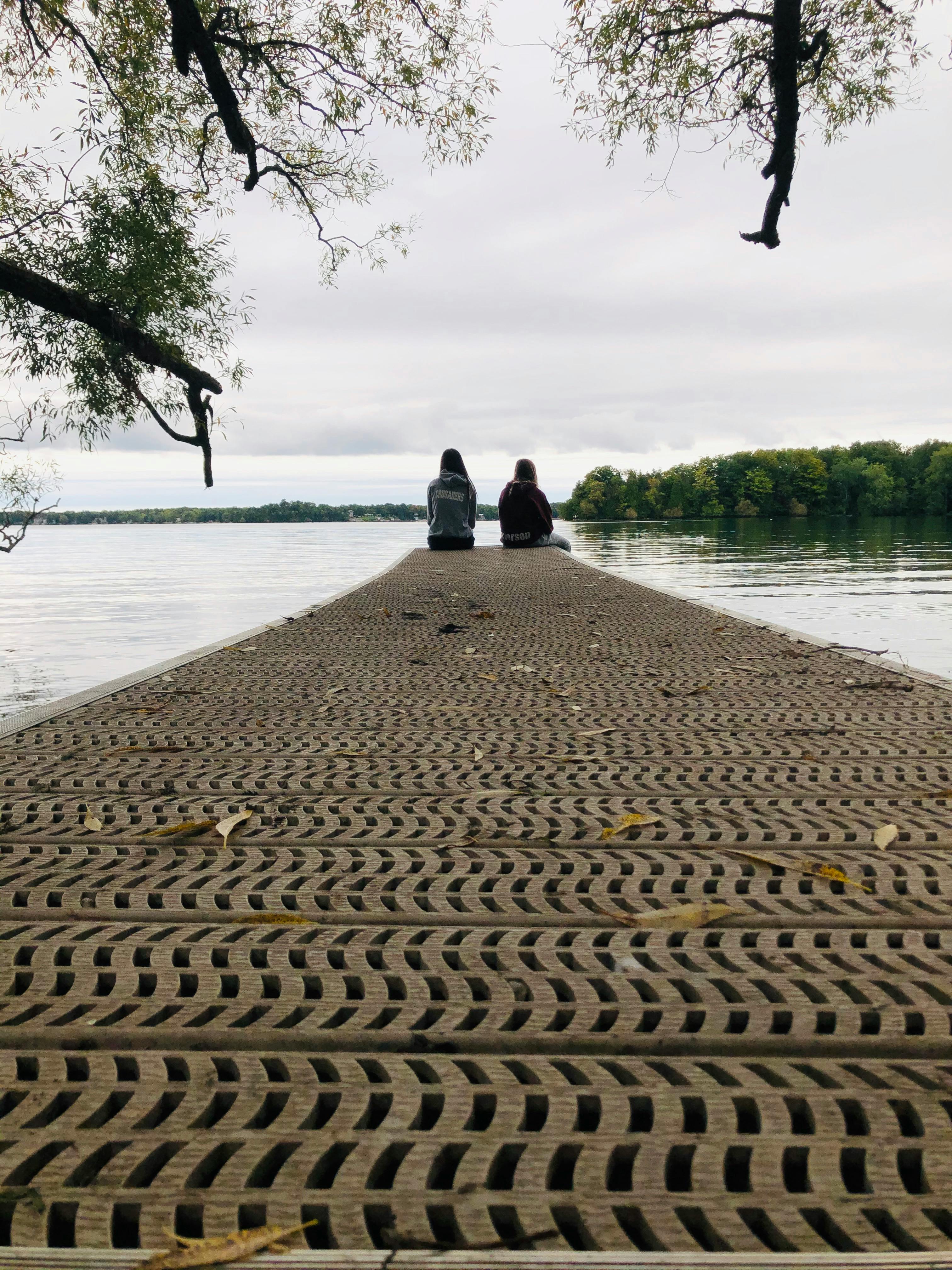 Women Sitting on Boardwalk on Lake · Free Stock Photo