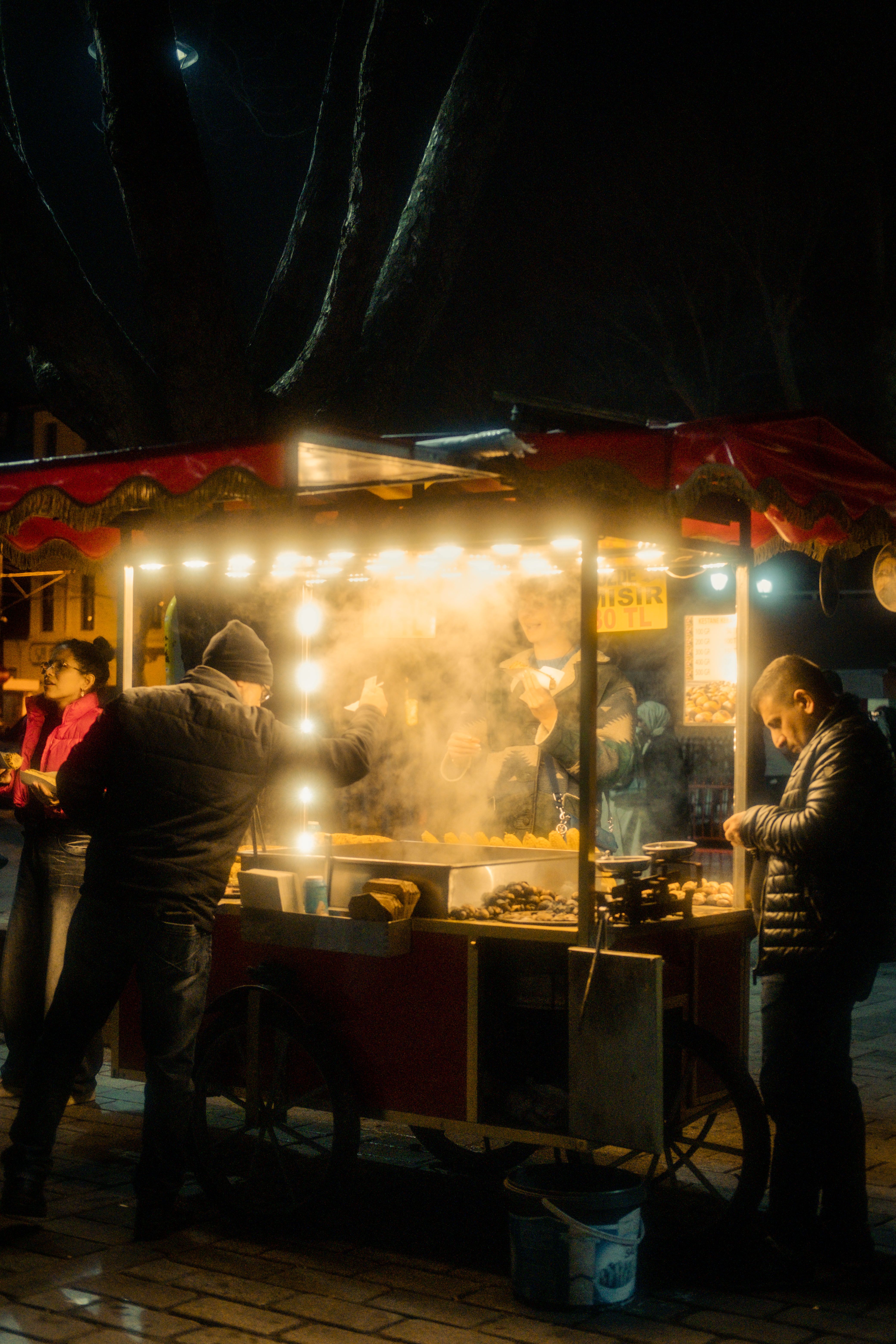 A food cart at night with people standing around it · Free Stock Photo