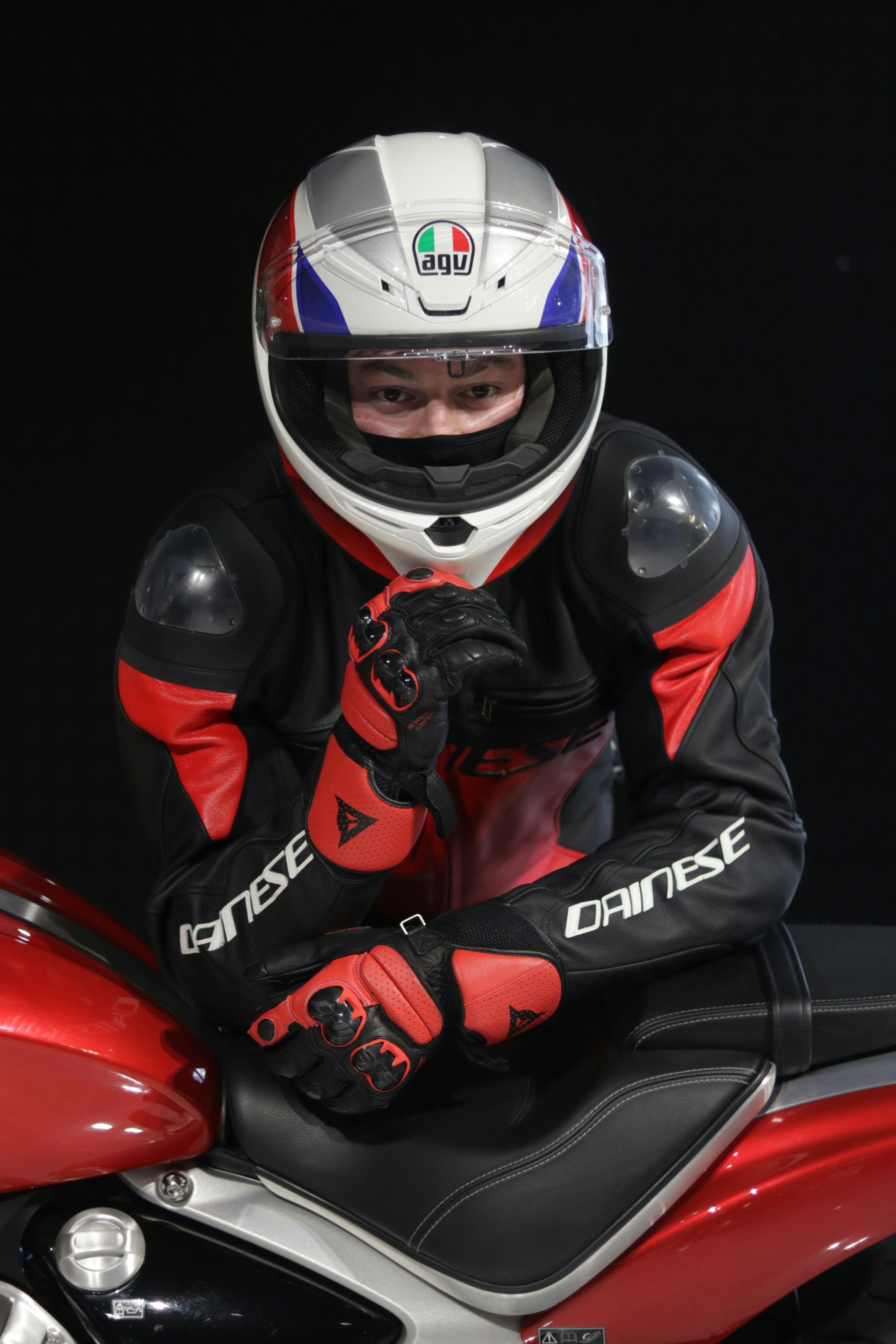 Man in Motorbike Suit Leaning on Motorcycle · Free Stock Photo