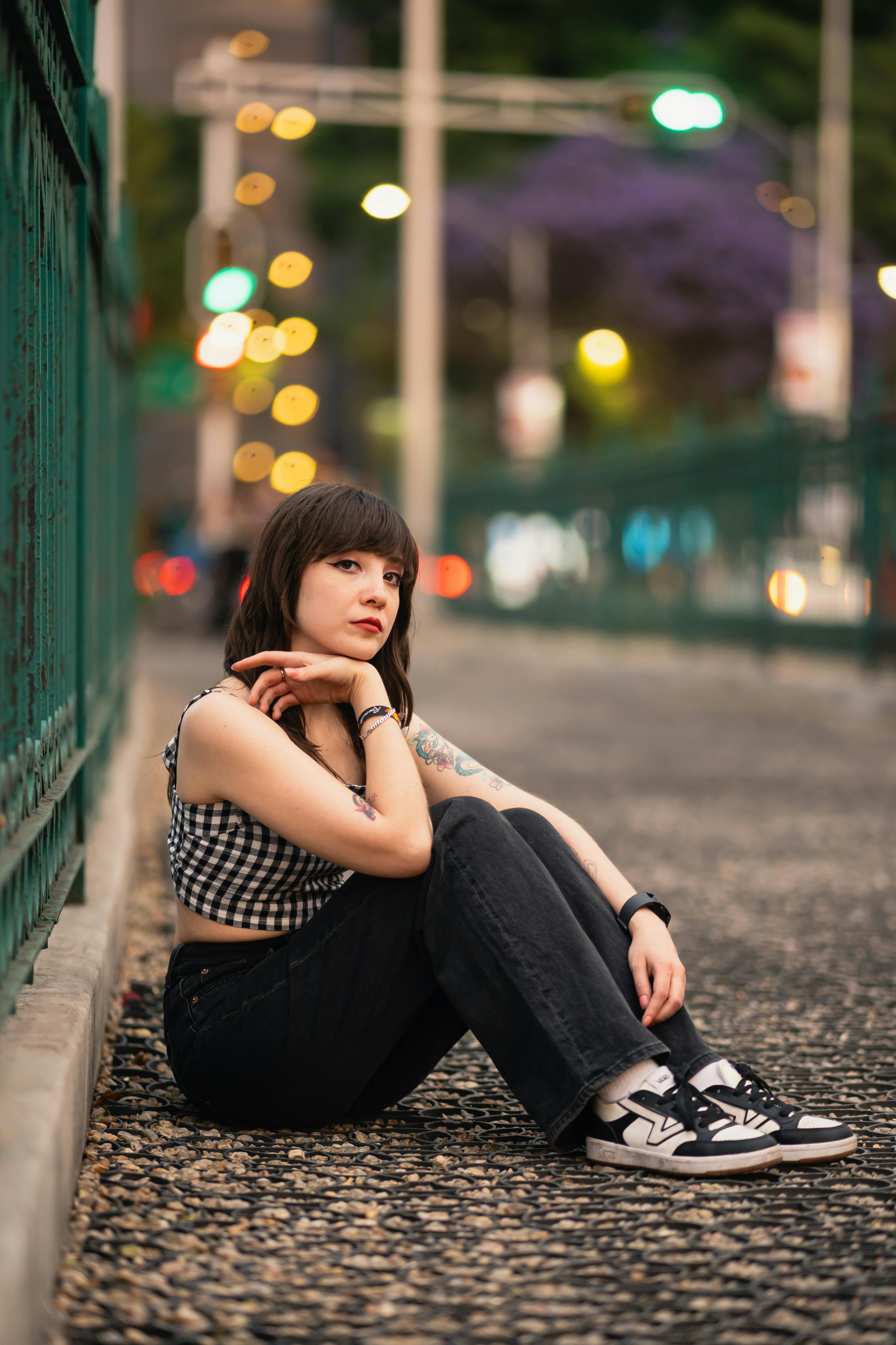 Woman in Check Crop Top Sits by Fence · Free Stock Photo