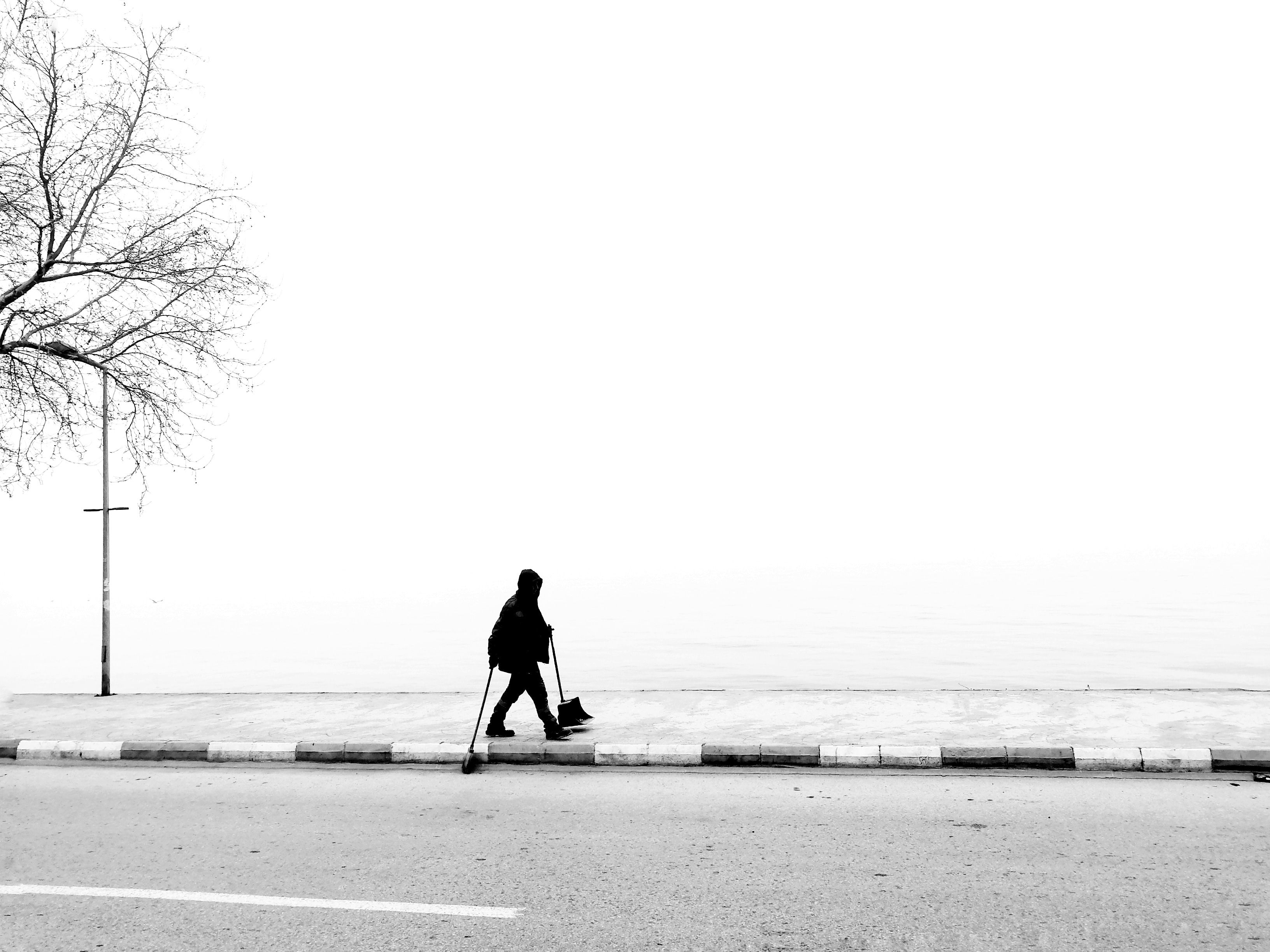 Cleaner with Broom Walking on Sidewalk near Road · Free Stock Photo