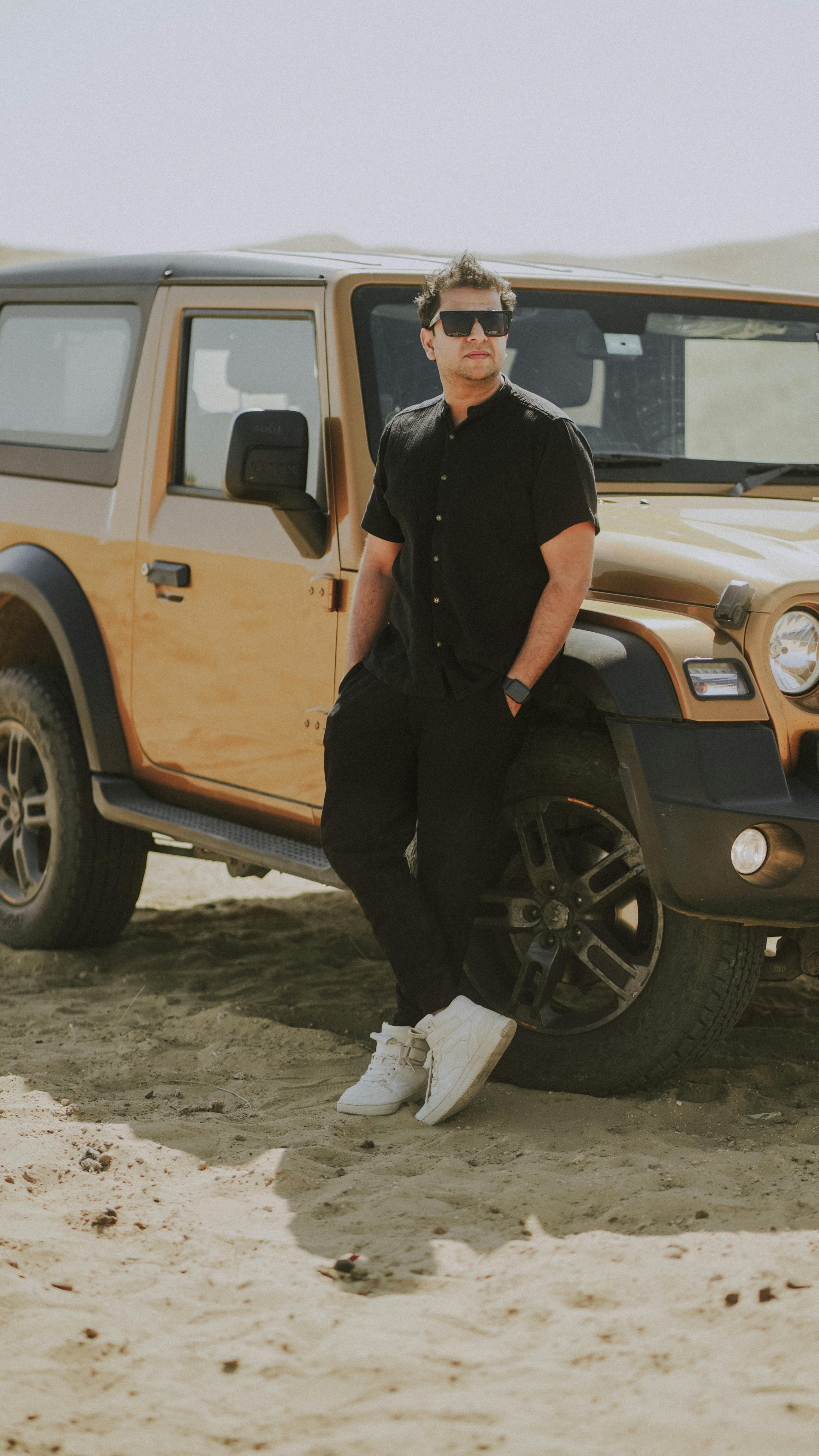 Driver Leaning Against an SUV Parked in the Desert · Free Stock Photo